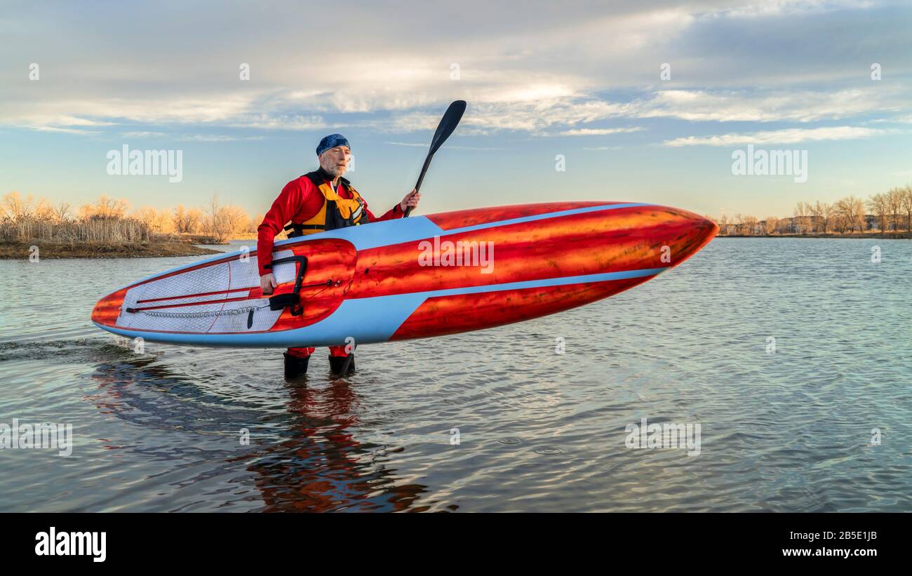 senior male paddler in a drysuit and life jacket is finishing his ...
