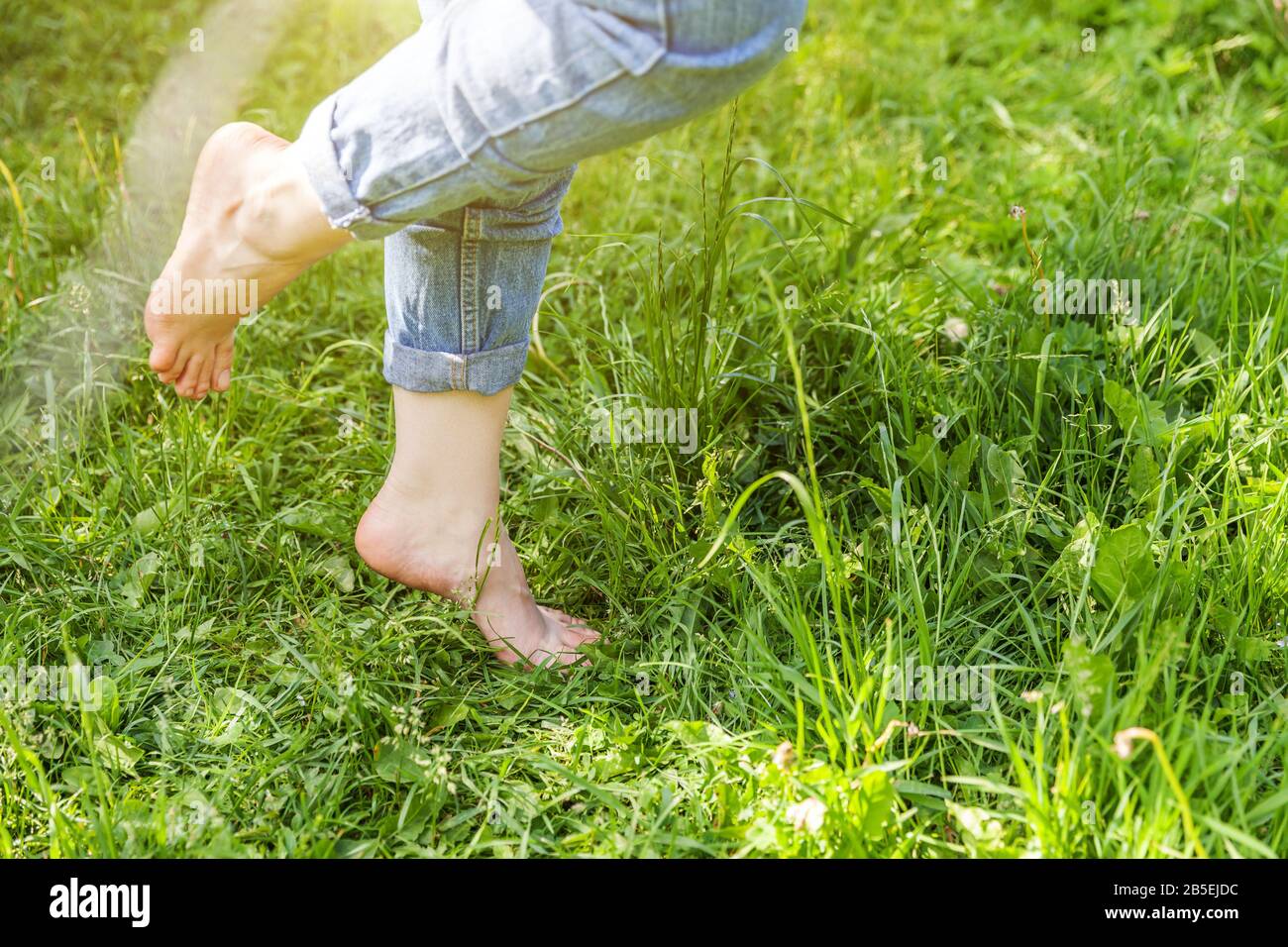 Two beautiful female feet walking on grass in sunny summer morning ...