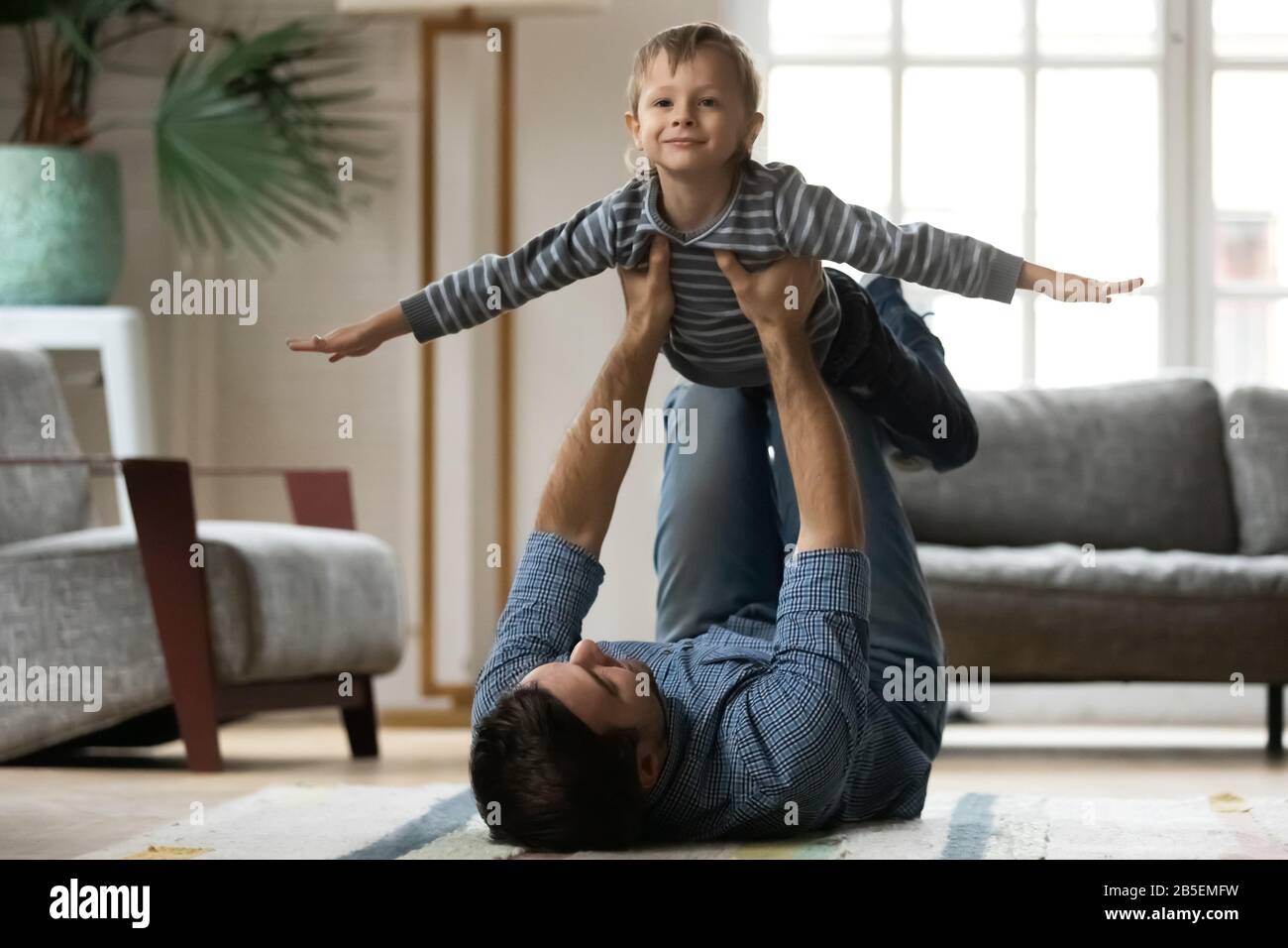 Young dad lifting small playful child son in air Stock Photo - Alamy