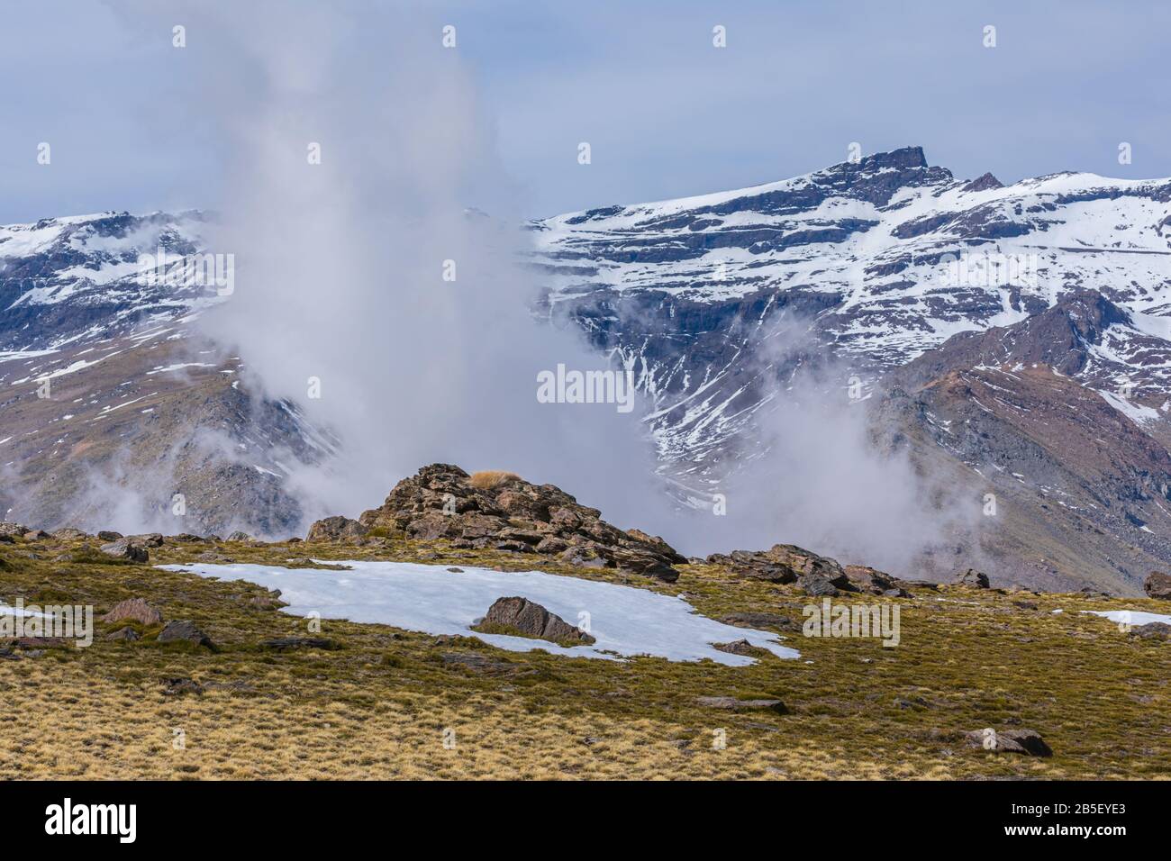 Clouds rising from a valley with a mountain in the background Stock ...