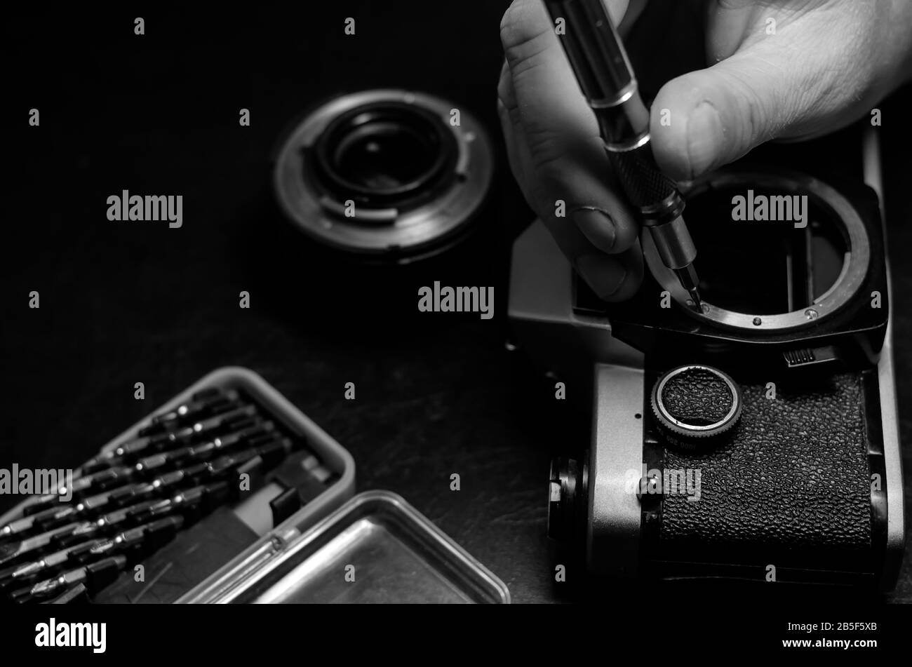 The hand unscrews the lens mount screws with a screwdriver. Repair an ...