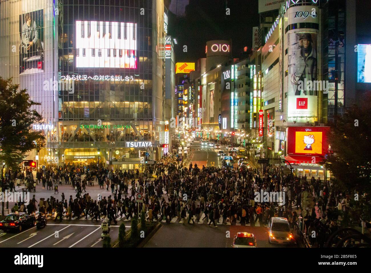 Night photography of a crowed of pedestrians crossing a four way zebra ...