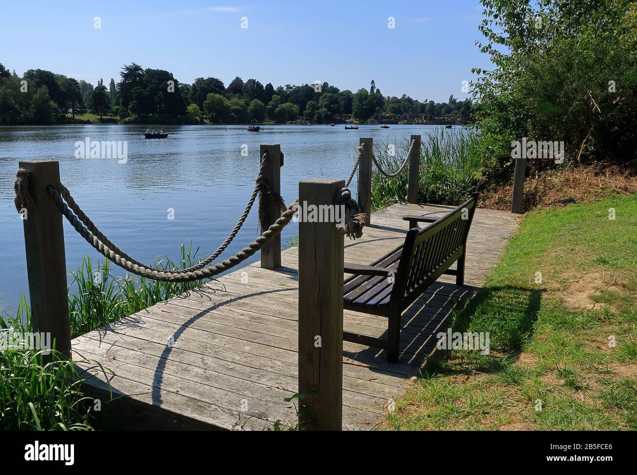 wooden bench overlookng a busy lake Stock Photo - Alamy