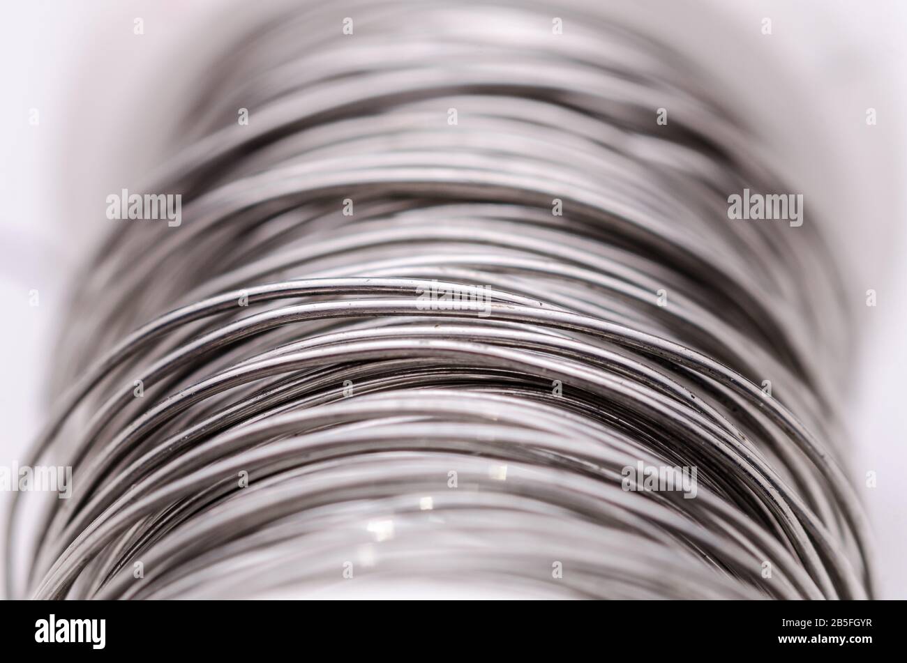 Metal wire on spindle, close up macro still life against white ...