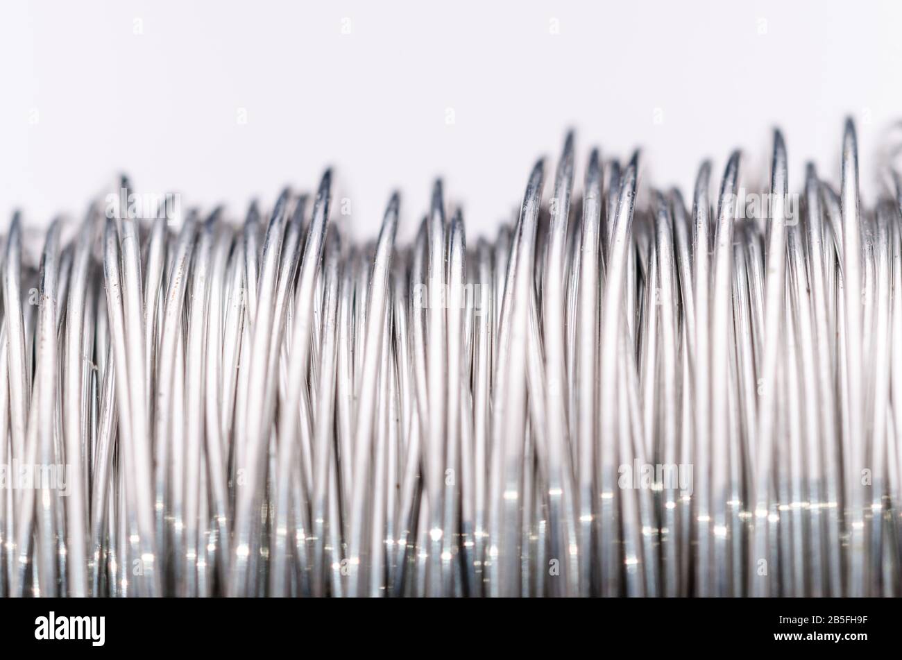Metal wire on spindle, close up macro still life against white ...