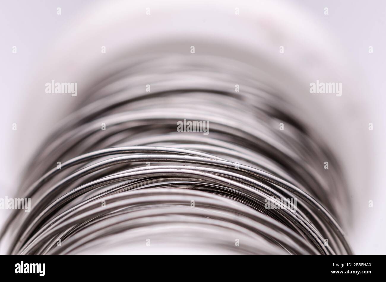 Metal wire on spindle, close up macro still life against white ...