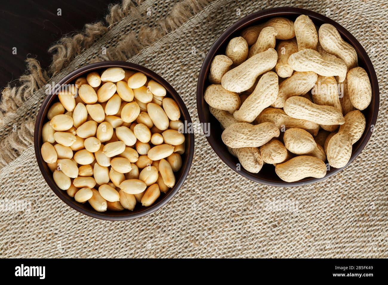 Peanuts in the shell and peeled closeup in a cup. Background with ...