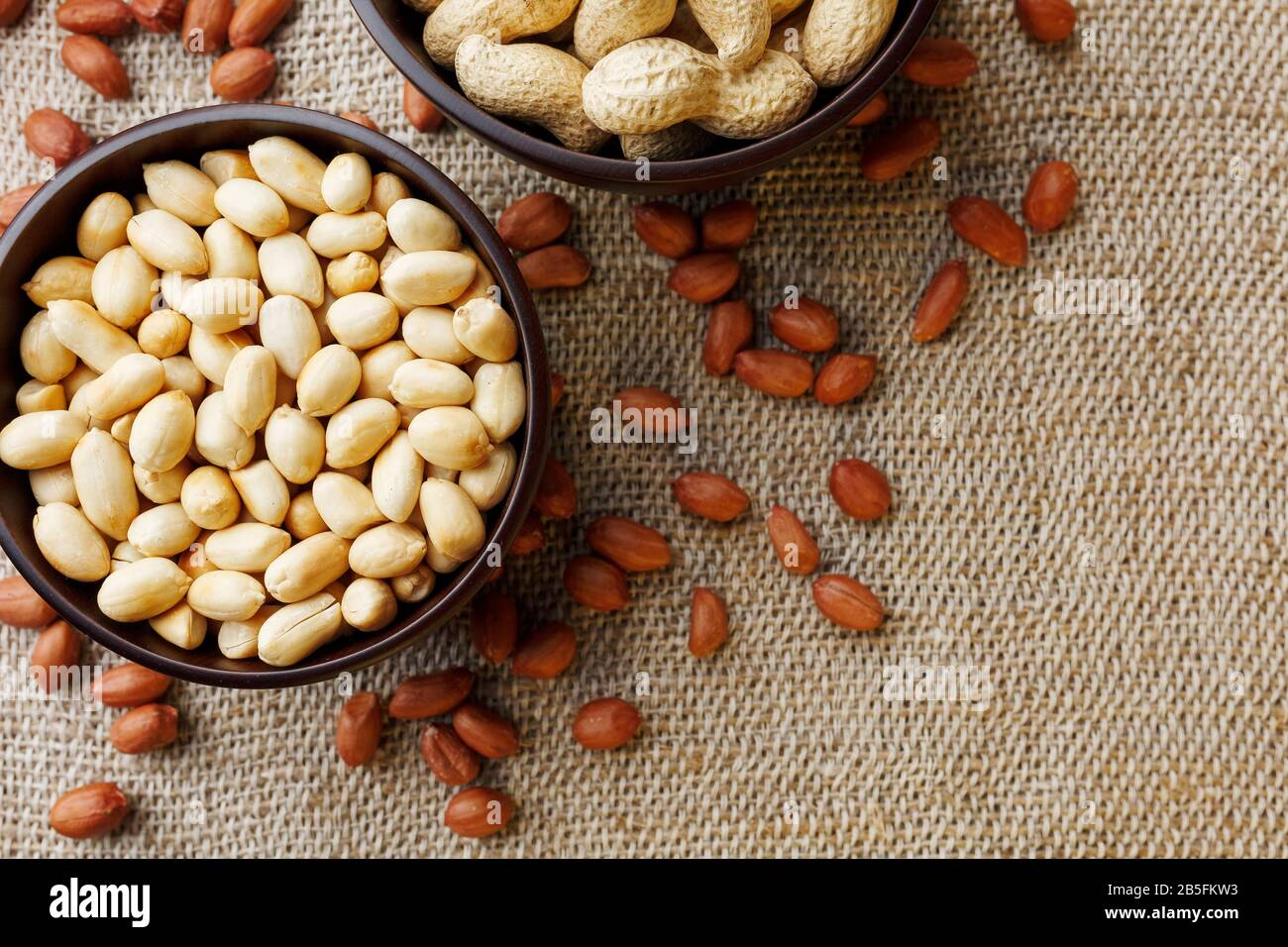 Peanuts in the shell and peeled closeup in a cup. Background with ...