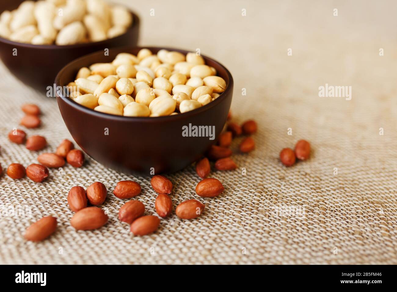 Peanuts in the shell and peeled closeup in a cup. Background with ...