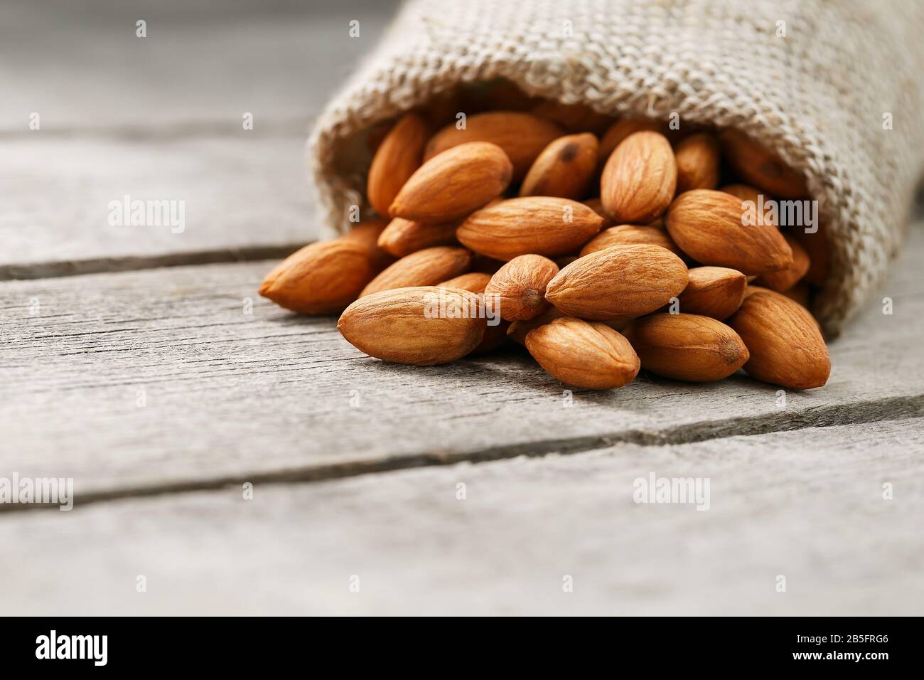 Almond nuts in a burlap bag on a wooden background. Macro almond nut ...