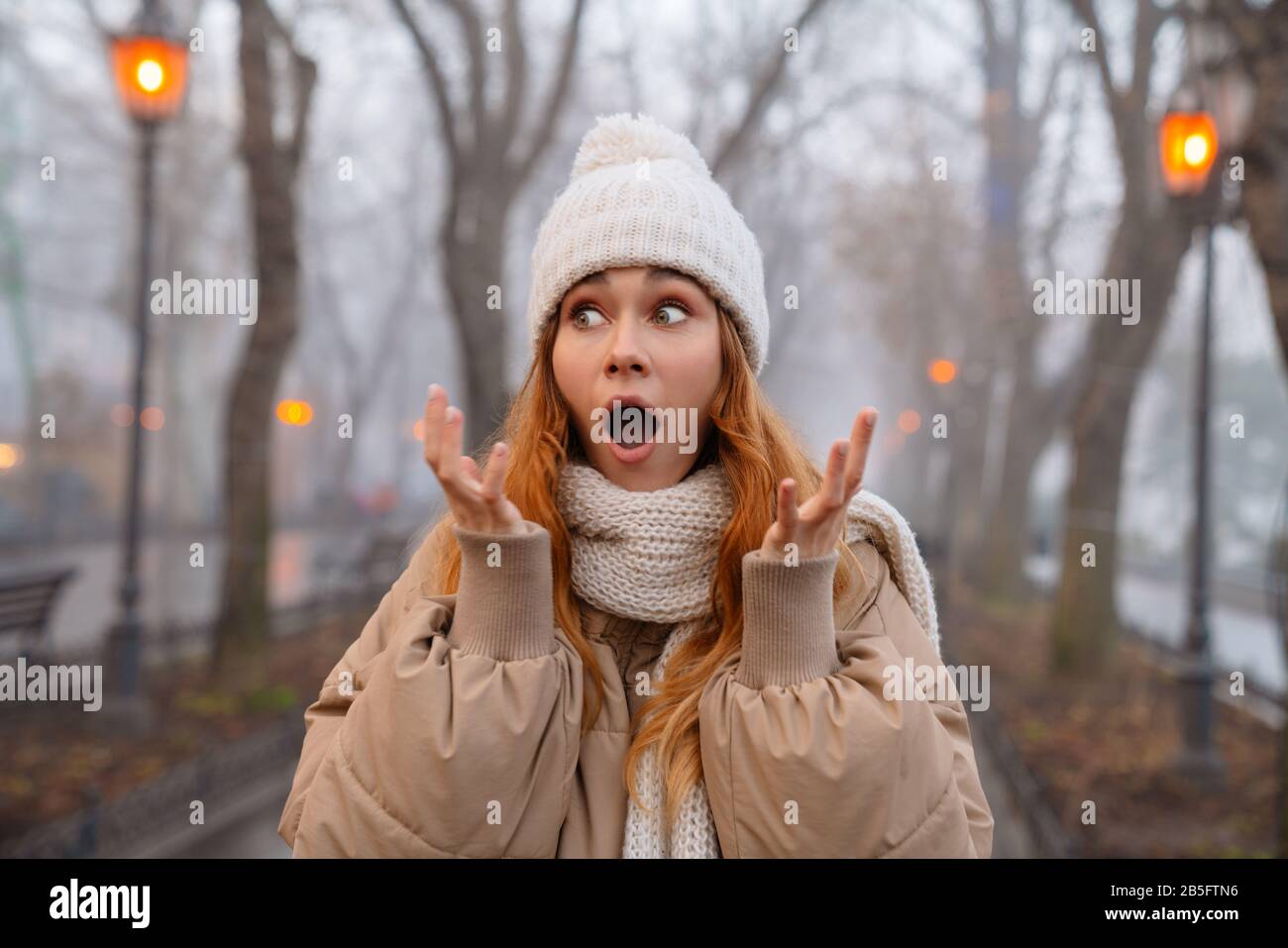 Attractive shocked young girl wearing winter clothes standing at the ...