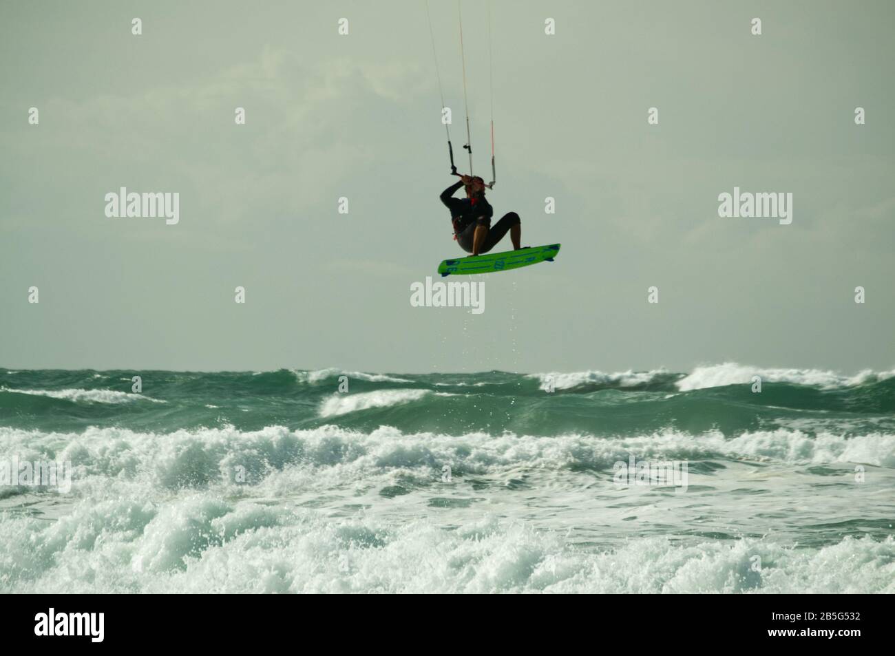 Kite surfer jumping over waves and flying through the air in rough seas ...