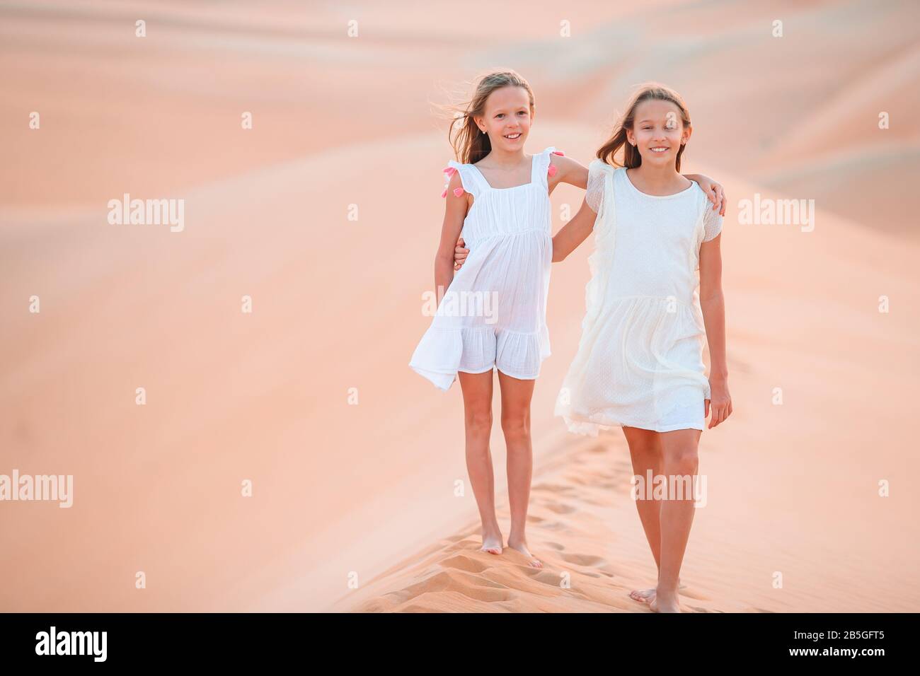 Girls among dunes in big desert in Emirates Stock Photo - Alamy