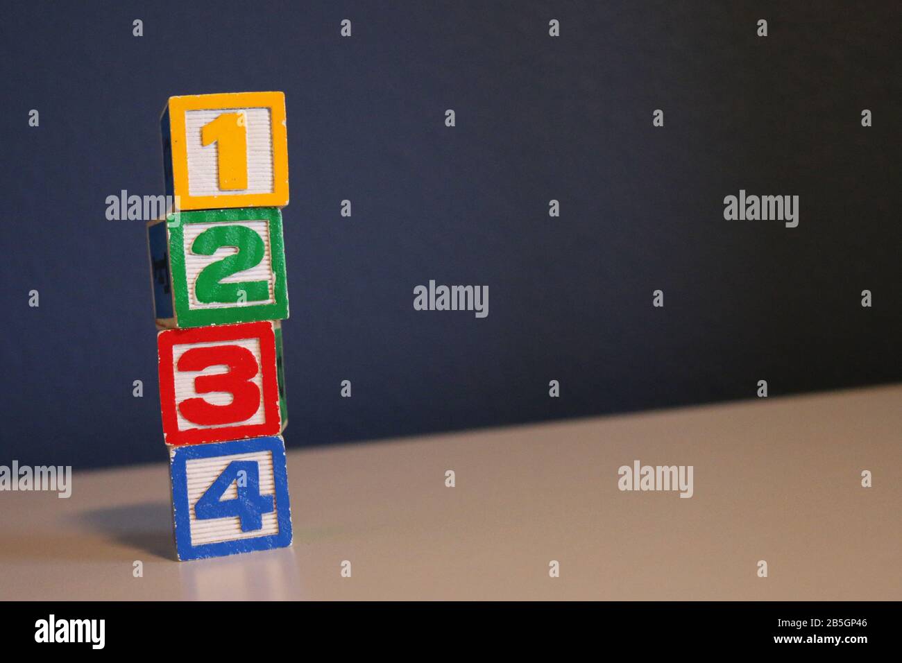 Vertical stack of colored alphabet wooden toy blocks on blue background ...