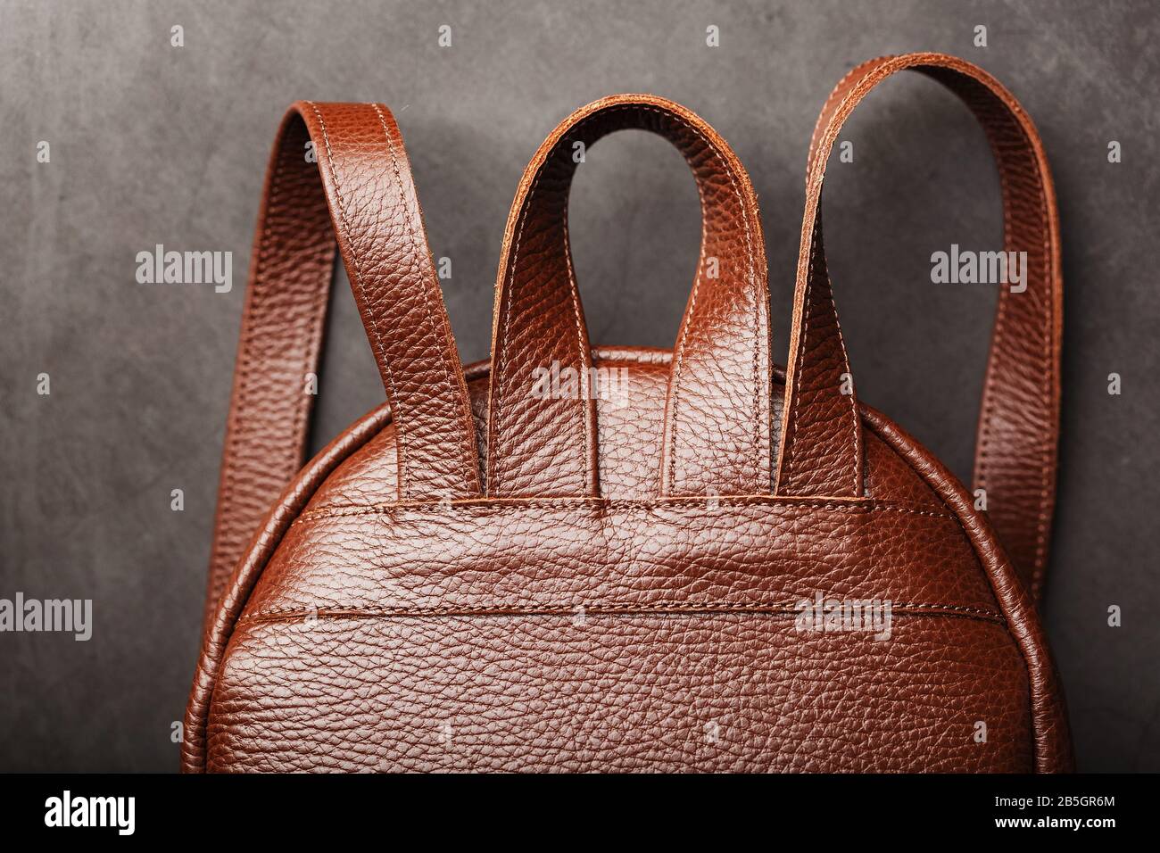 Brown backpack made of textured brown leather on a black stone ...