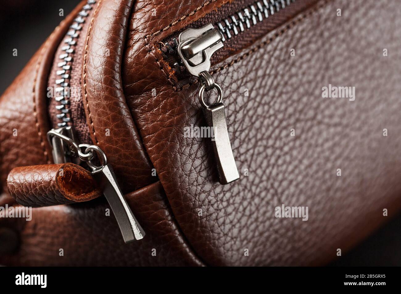 A brown belt bag made of textured brown leather on a black stone ...