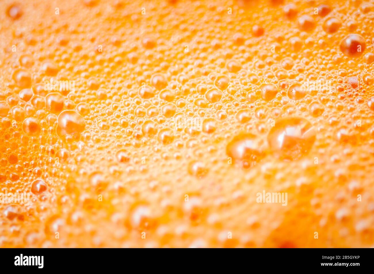 Orange and carrot juice smoothie bubble froth full frame background ...