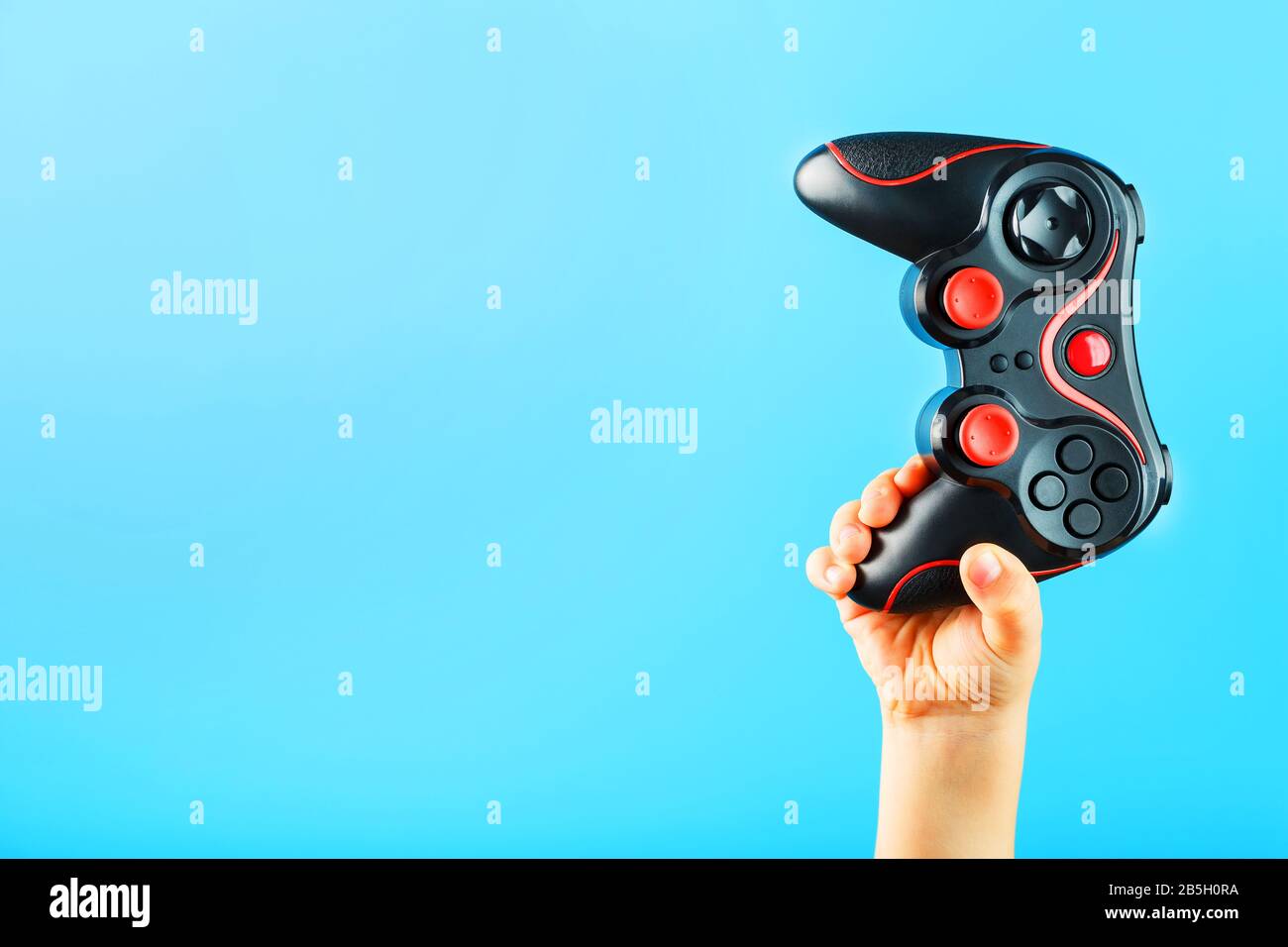 A child's hand triumphantly holds the gamepad on a blue background ...