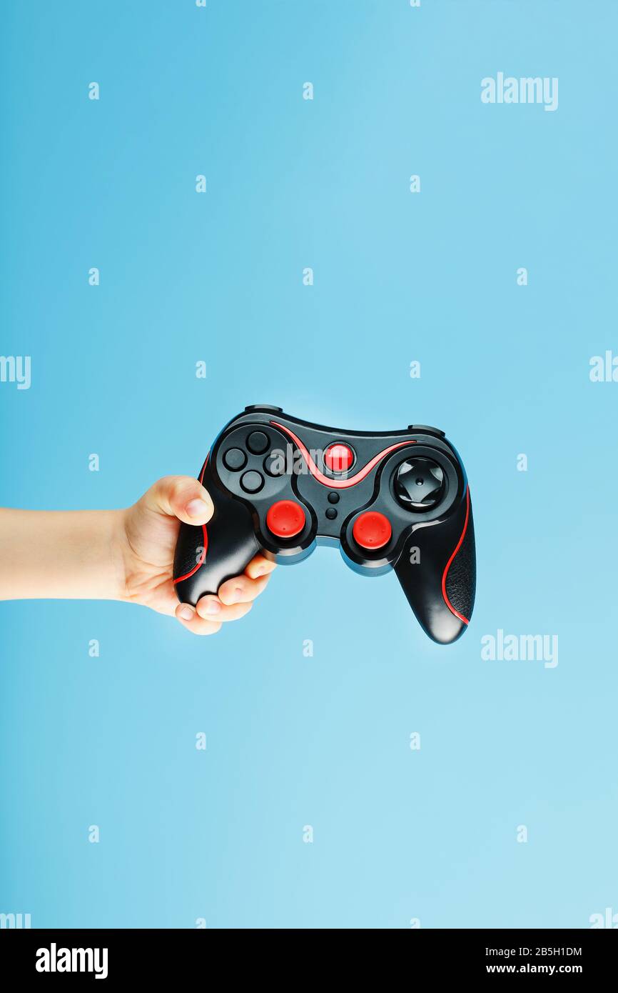 A gamepad on a blue background holds a child's hand as a weapon ...