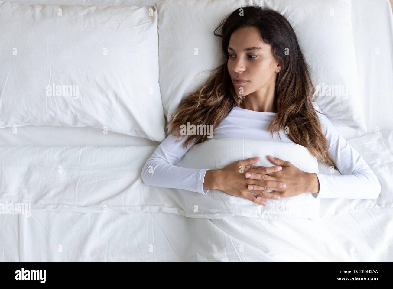 Pensive young woman lying alone in bed thinking Stock Photo - Alamy