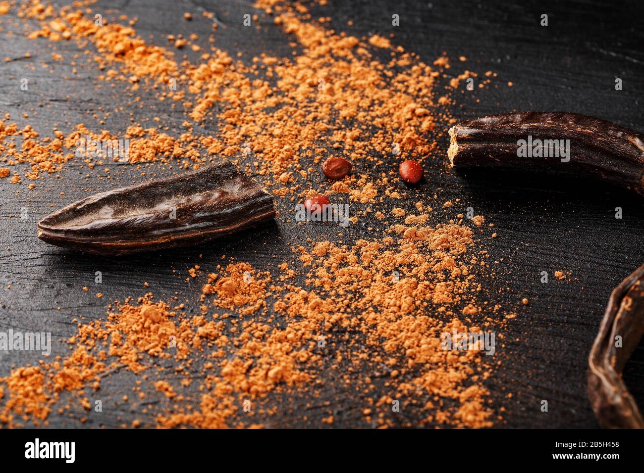 Carob carob fruit with powder on black background. Blast the Sweet ...