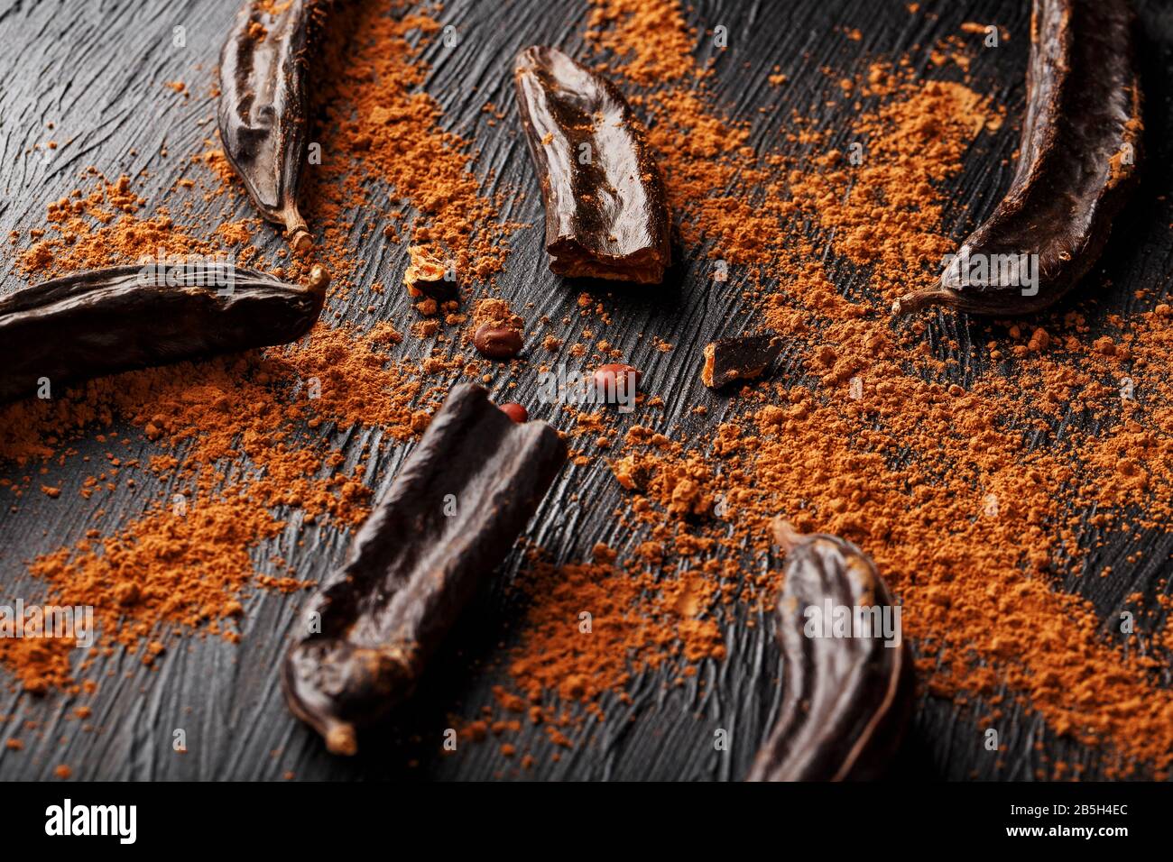 Carob carob fruit with powder on black background. Blast the Sweet ...