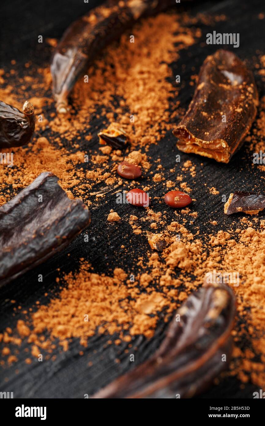Carob carob fruit with powder on black background. Blast the Sweet ...