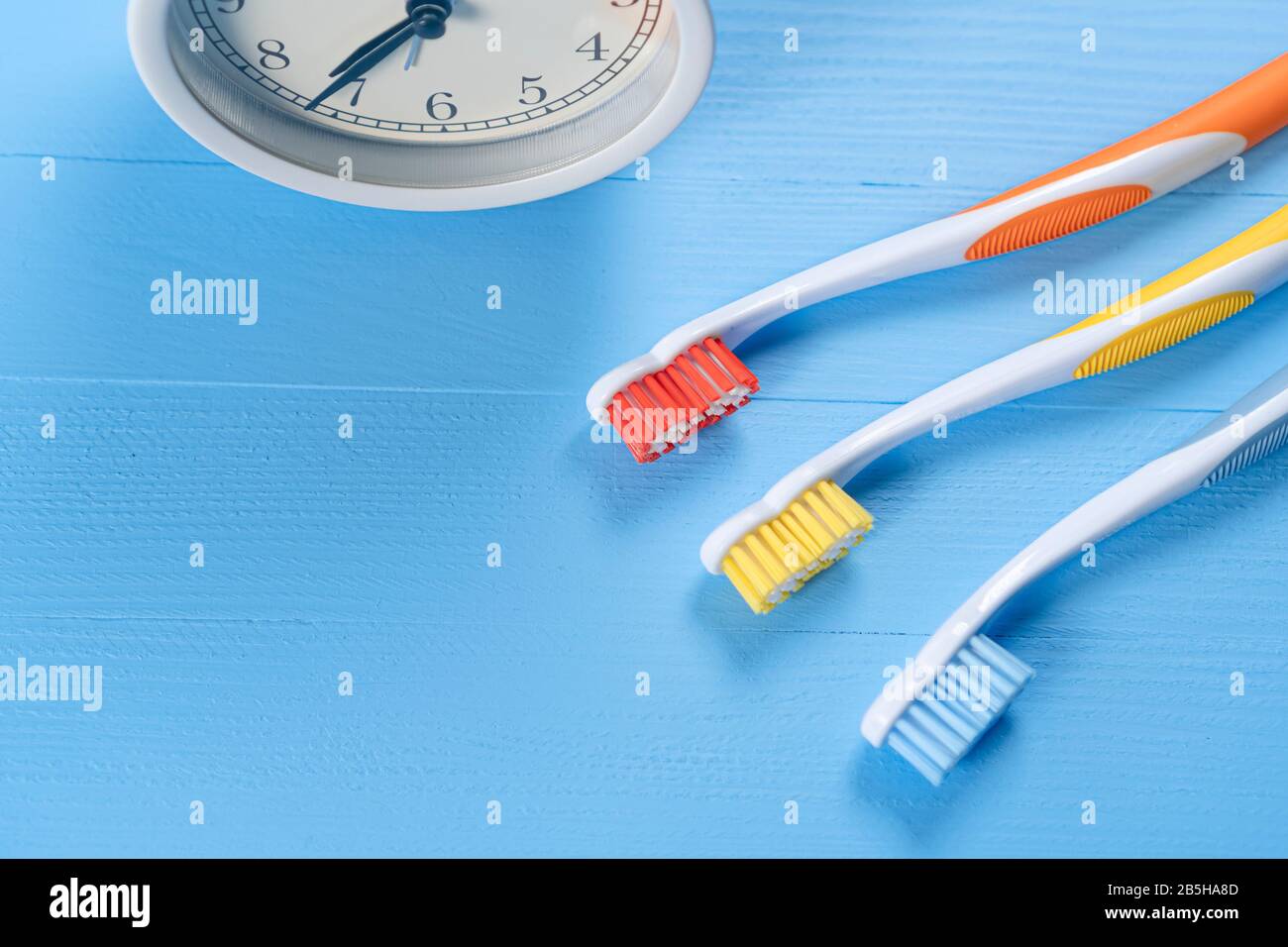 Three bright toothbrushes on a light blue background. Orange and yellow ...