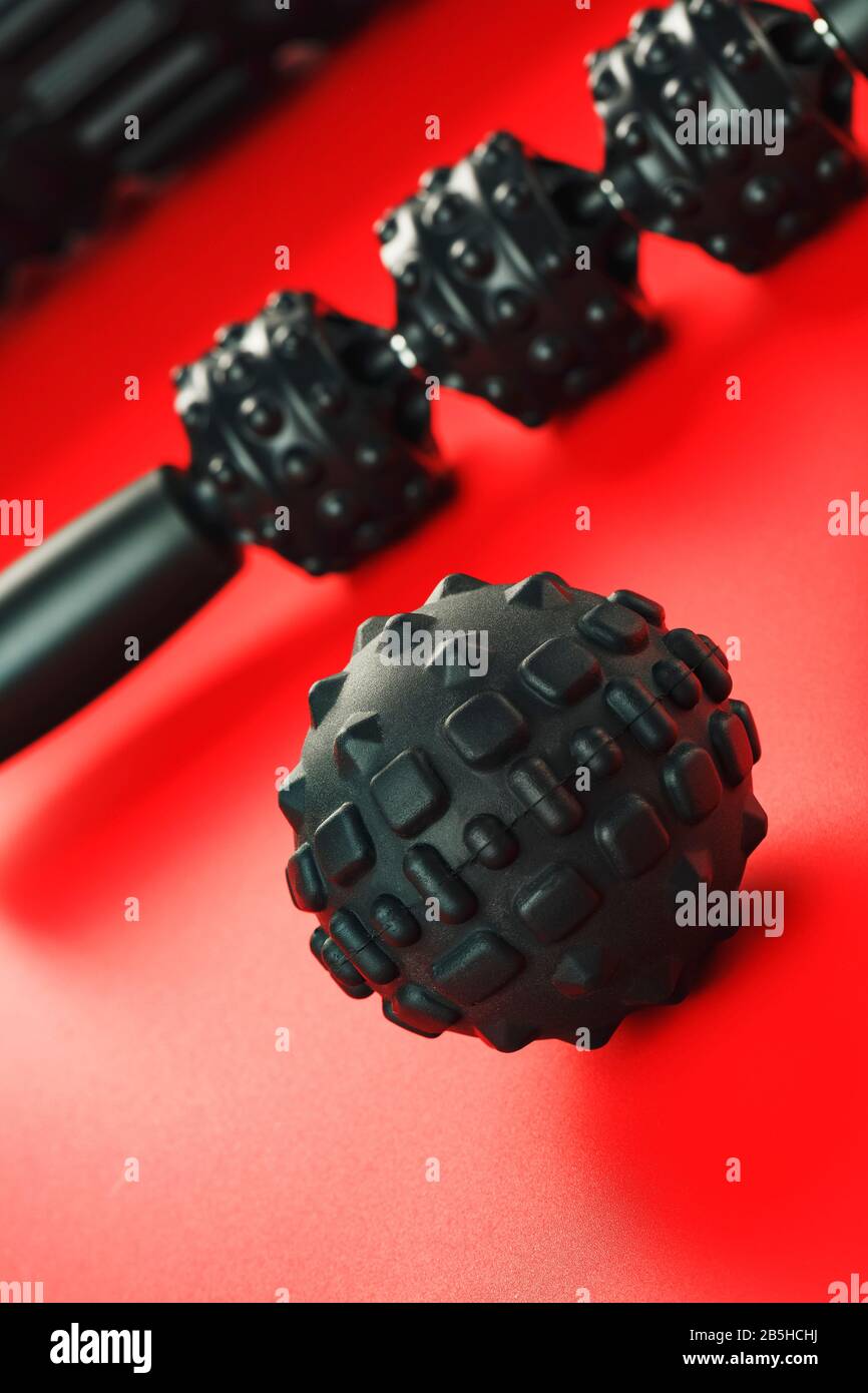 Set of Black lumpy foam massage roller, body roller, rubber ball on red ...