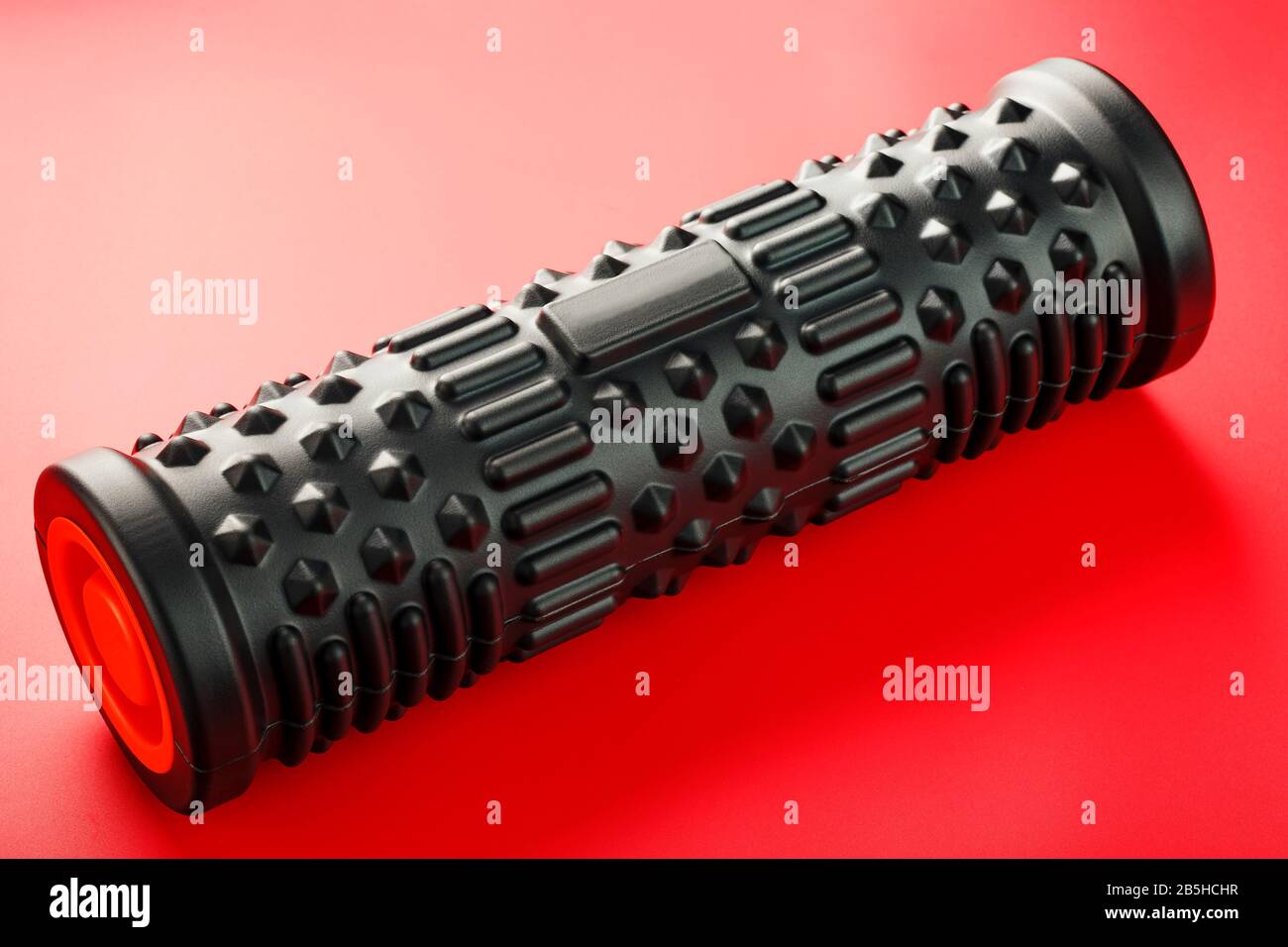 Black lumpy foam massage roller, body roller, rubber ball on red ...