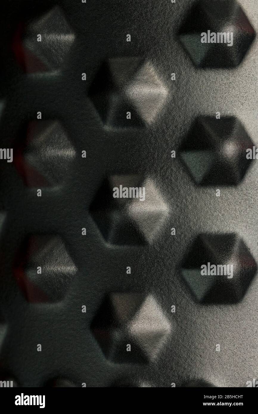 Black lumpy foam massage roller on red background. For the mechanical ...