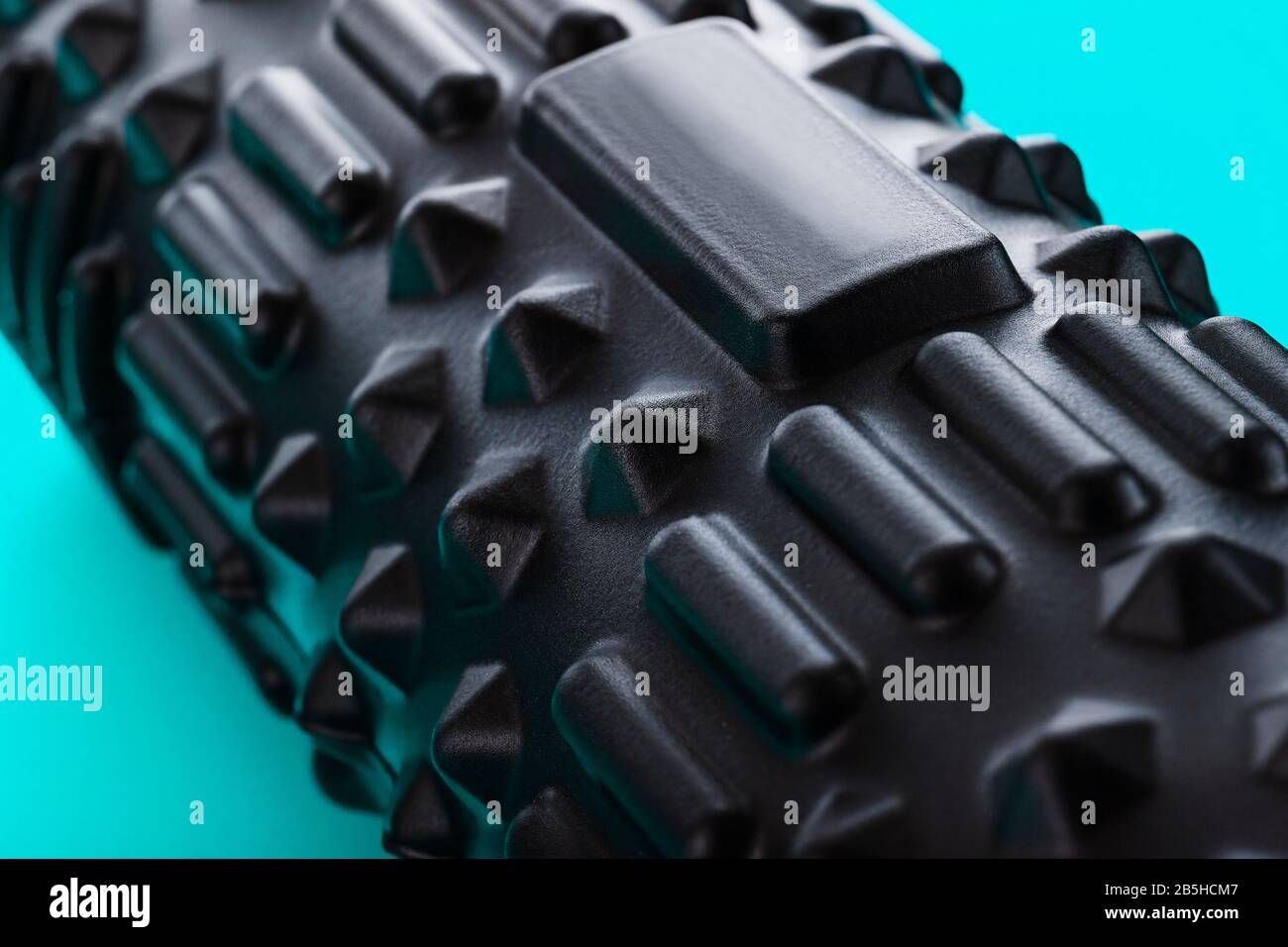 Black bumpy foam massage roller, body roller on blue background. For ...