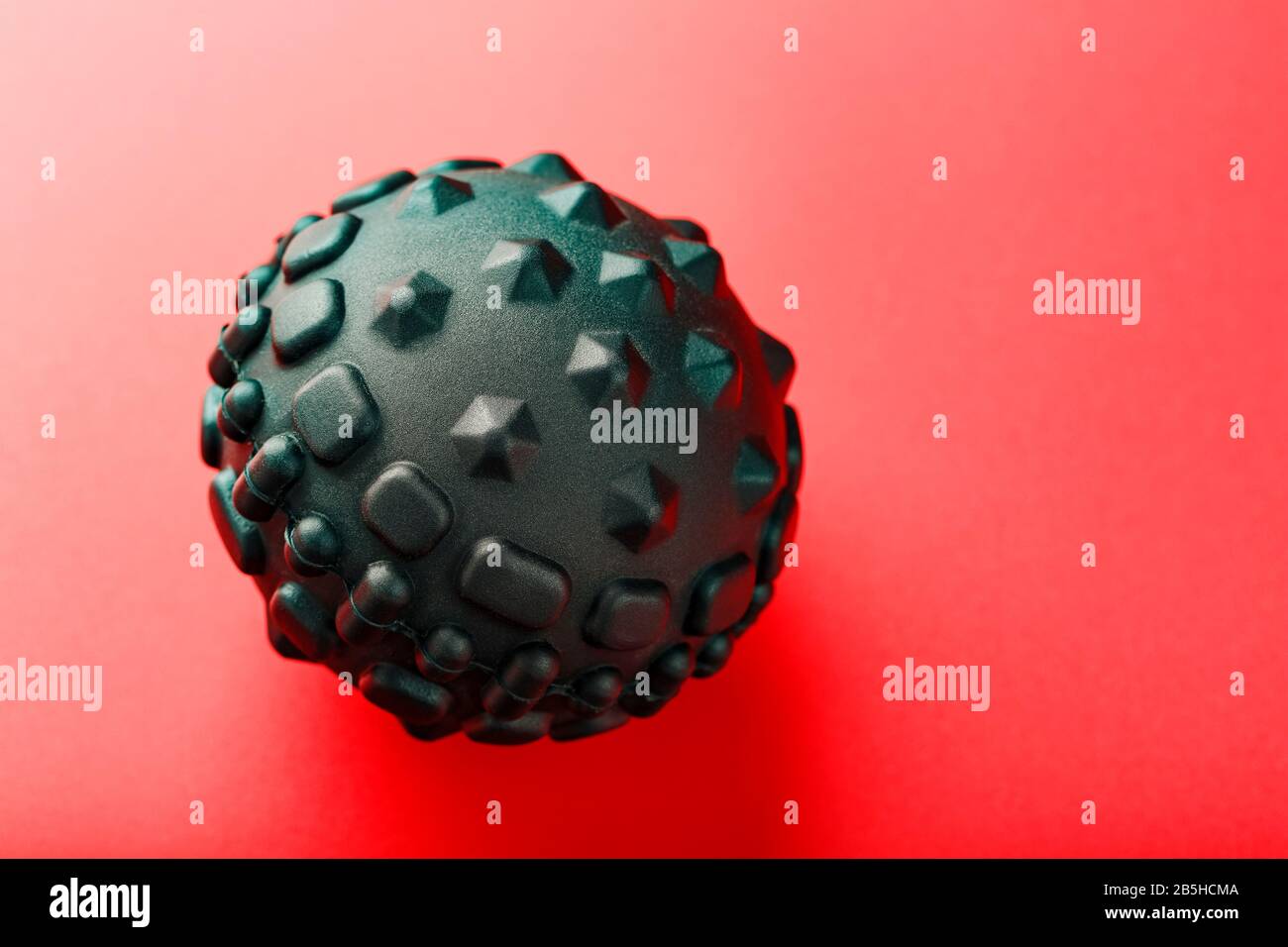 Black lumpy foam body massage ball on red background. For the ...