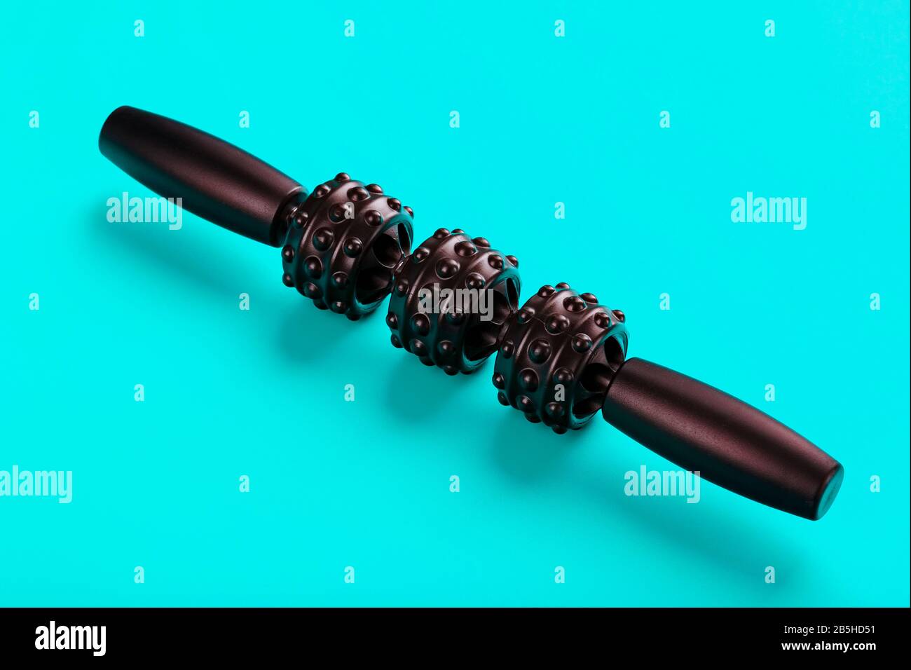 Black bumpy foam body massage roller on a blue background. For the ...