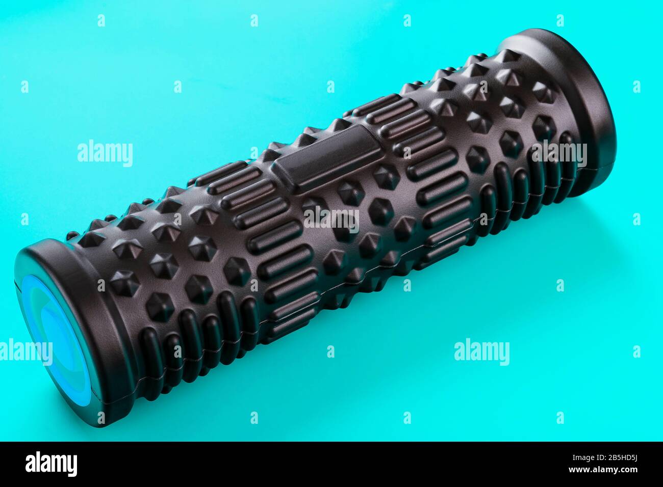 Black bumpy foam massage roller, body roller on blue background. For ...