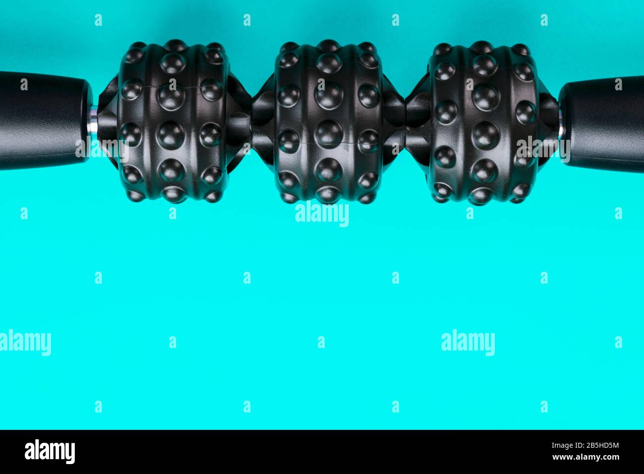 Black bumpy foam body massage roller on a blue background. For the ...