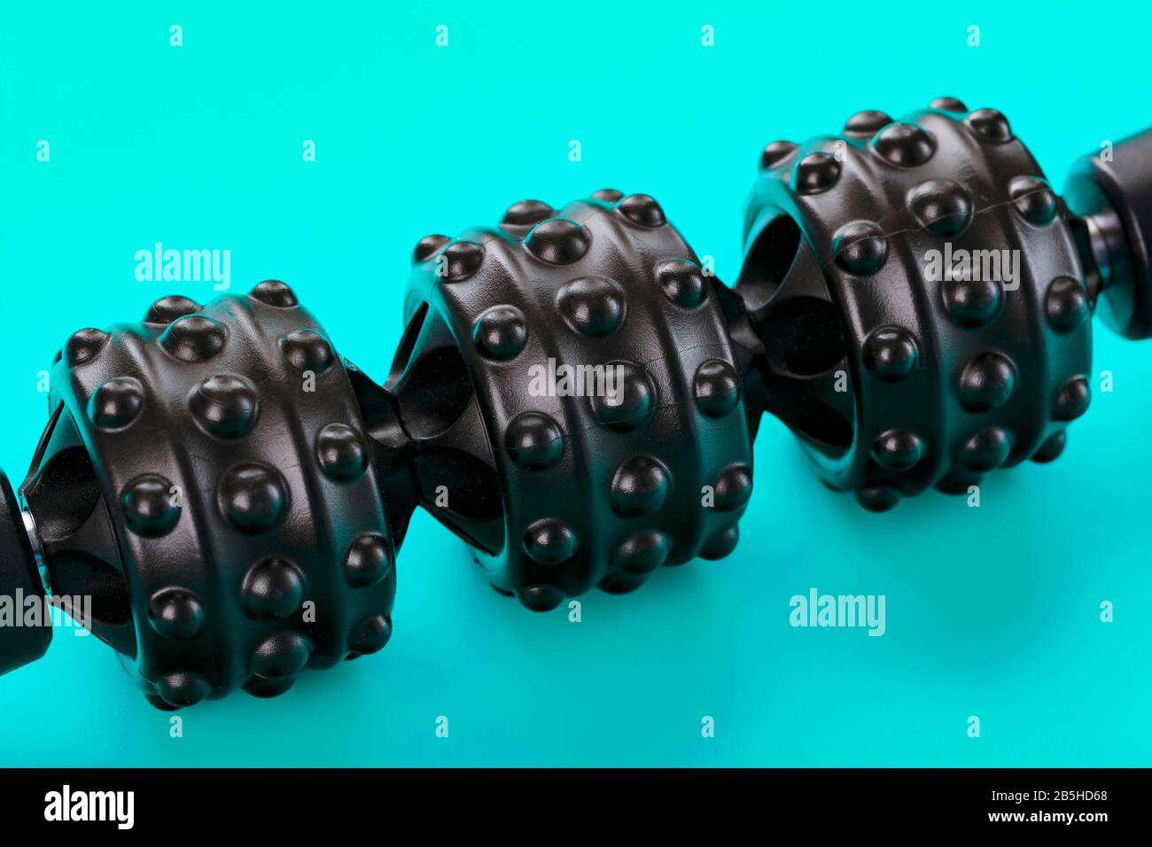 Black bumpy foam body massage roller on a blue background. For the ...