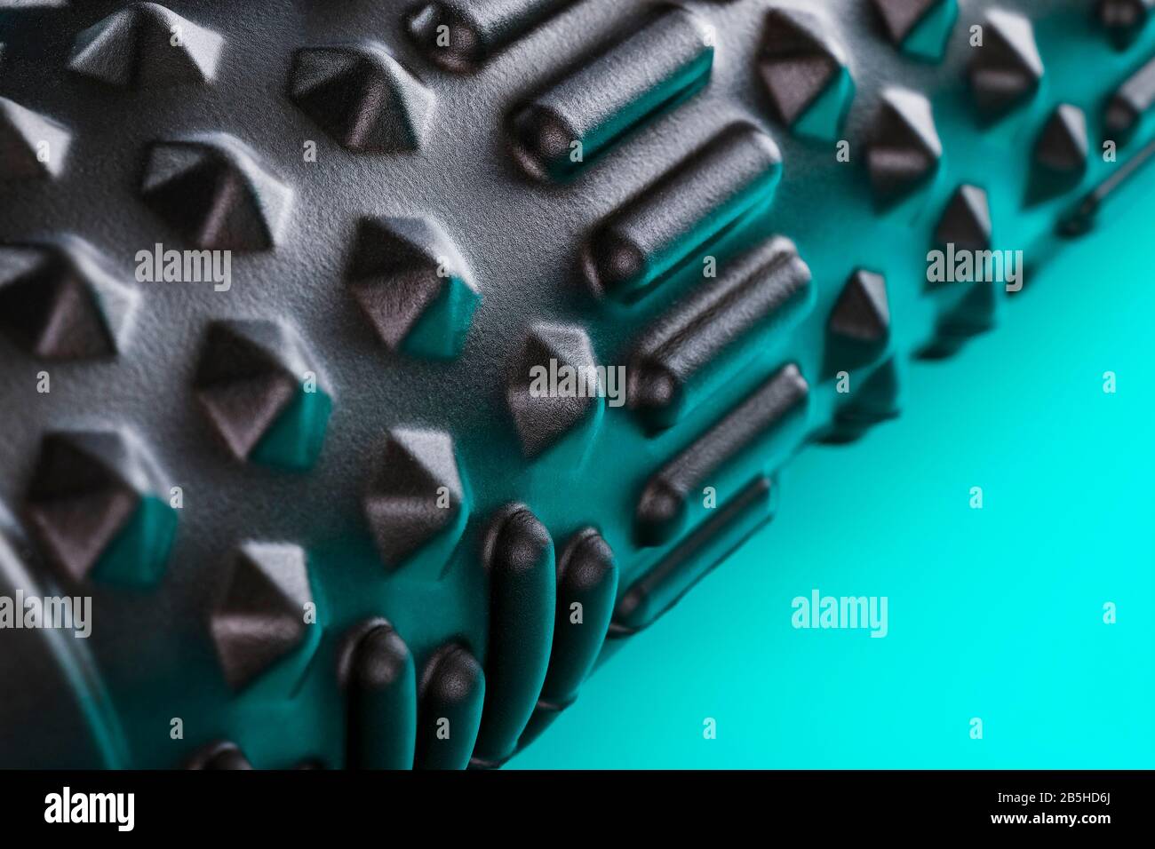 Black bumpy foam massage roller, body roller on blue background. For ...