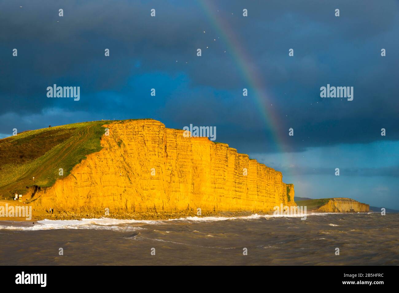 West Bay, Dorset, UK. 8th March 2020. UK Weather. A rainbow arches ...