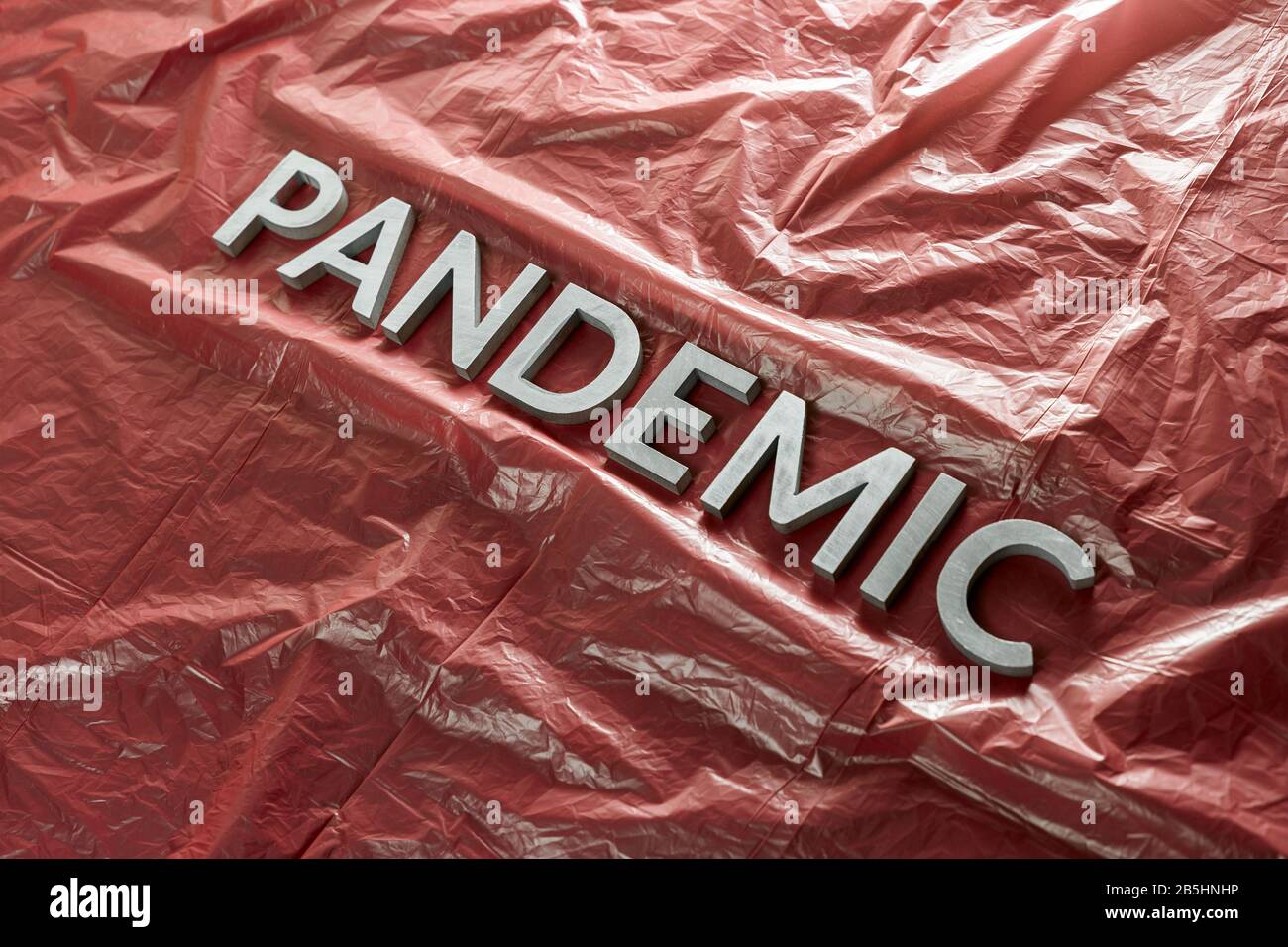 the word pandemic laid with silver letters on crumpled red plastic film ...