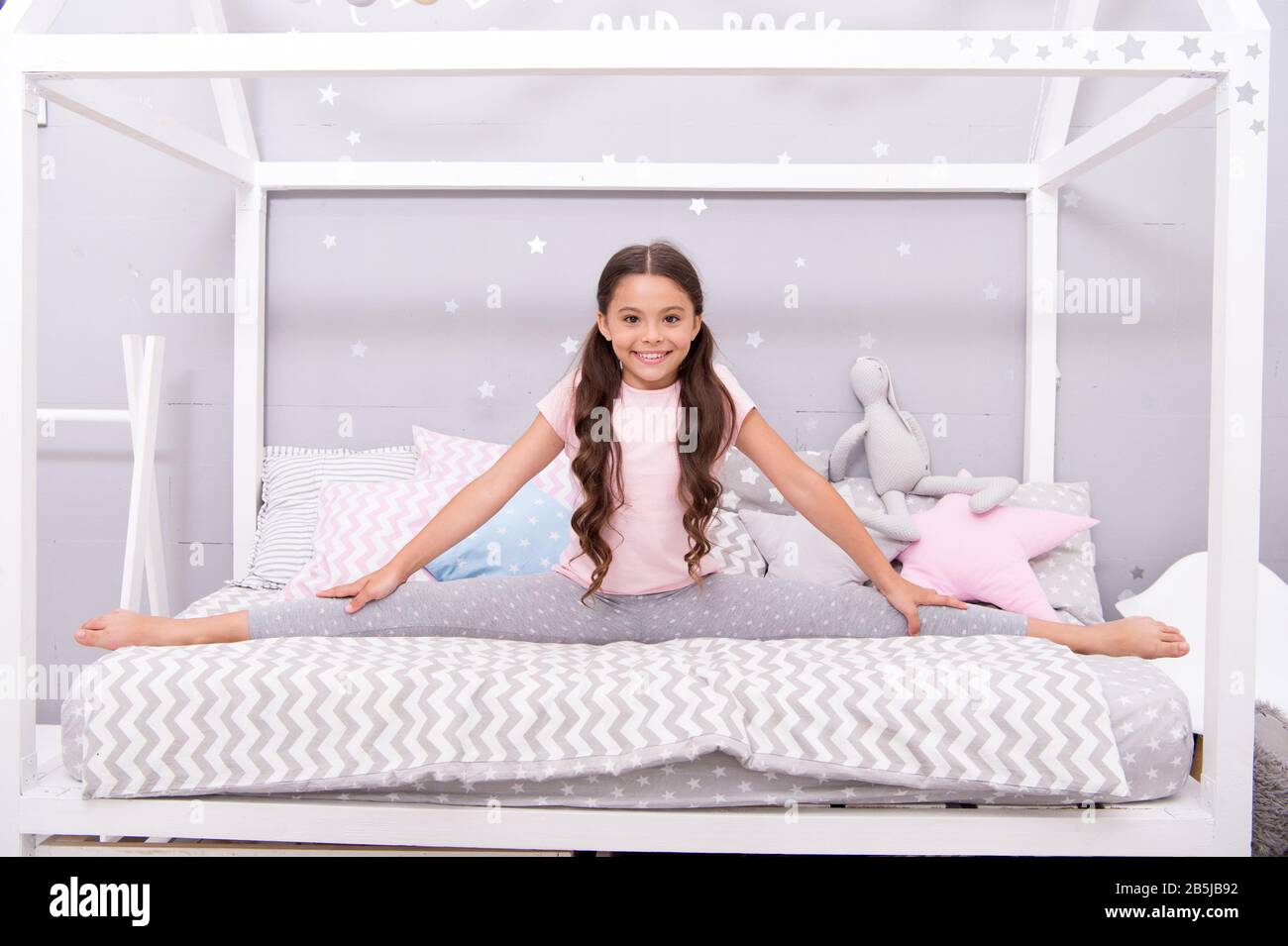 Being fit and flexible. Athletic girl do leg split on bed. Fitness and ...