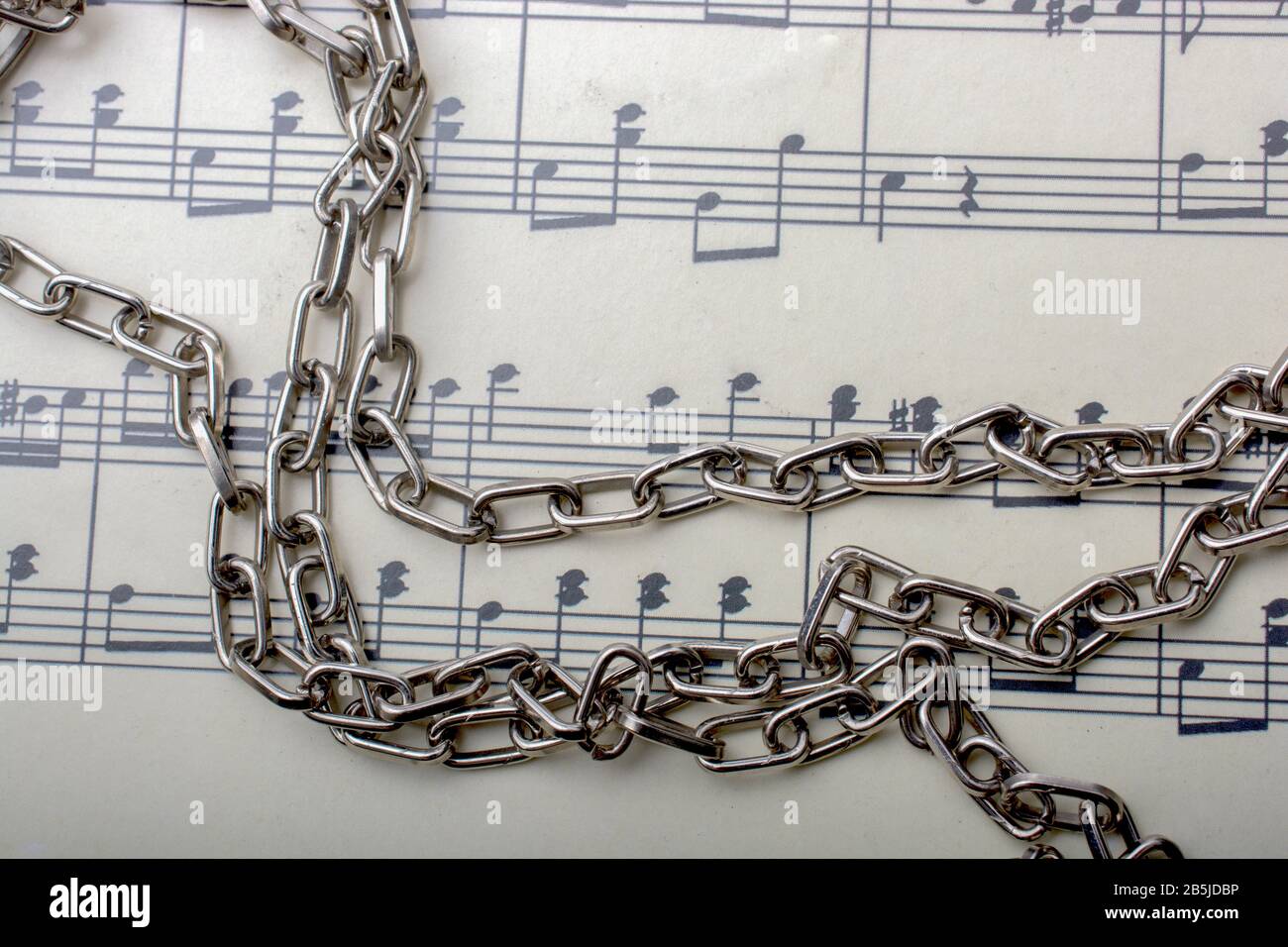 Metal chain placed on a paper with musical notes Stock Photo - Alamy