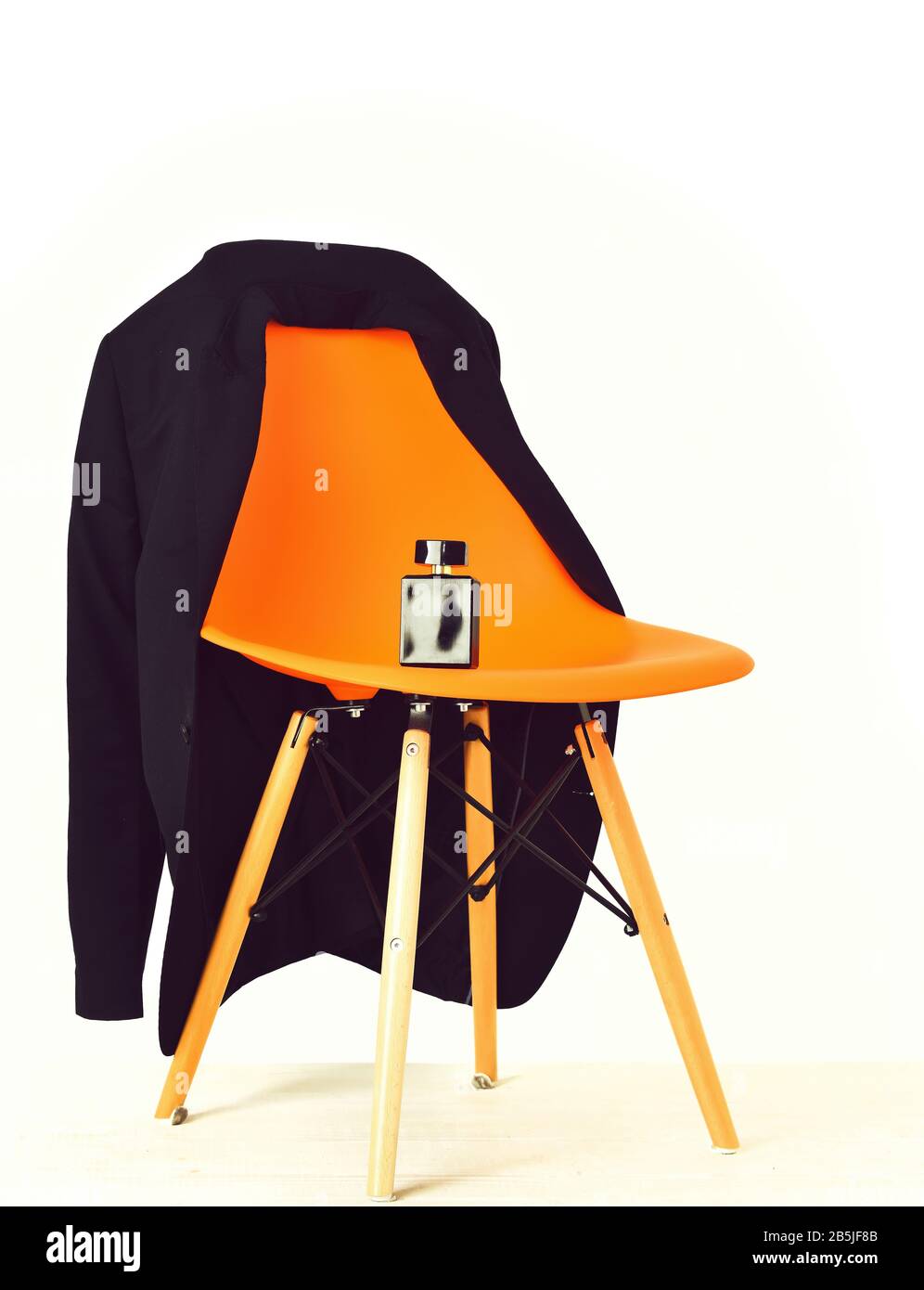 Orange plastic office chair with black jacket and bottle of perfume ...