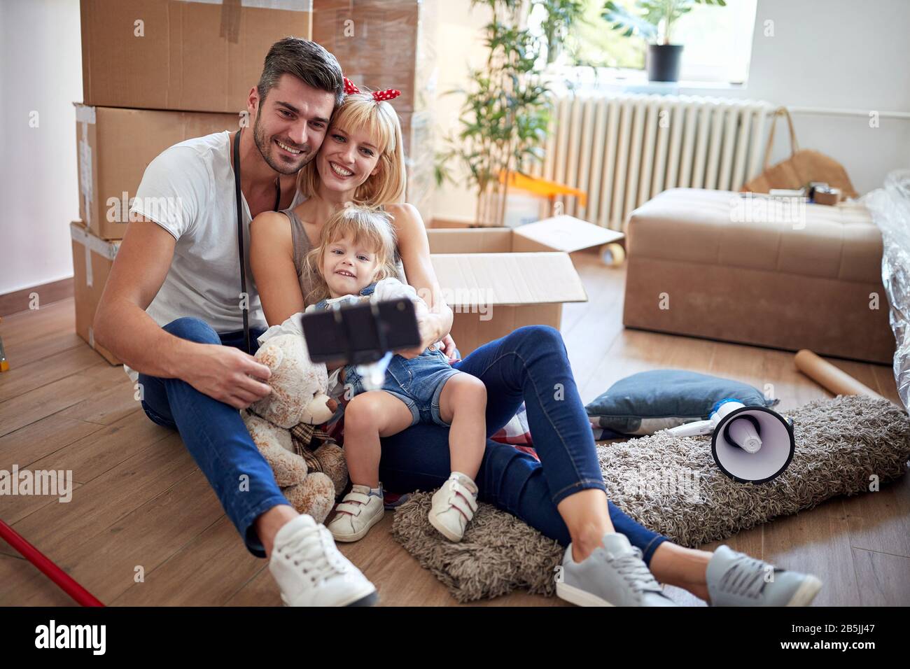 young family taking selfie in new apartment with unpacked stuff in ...