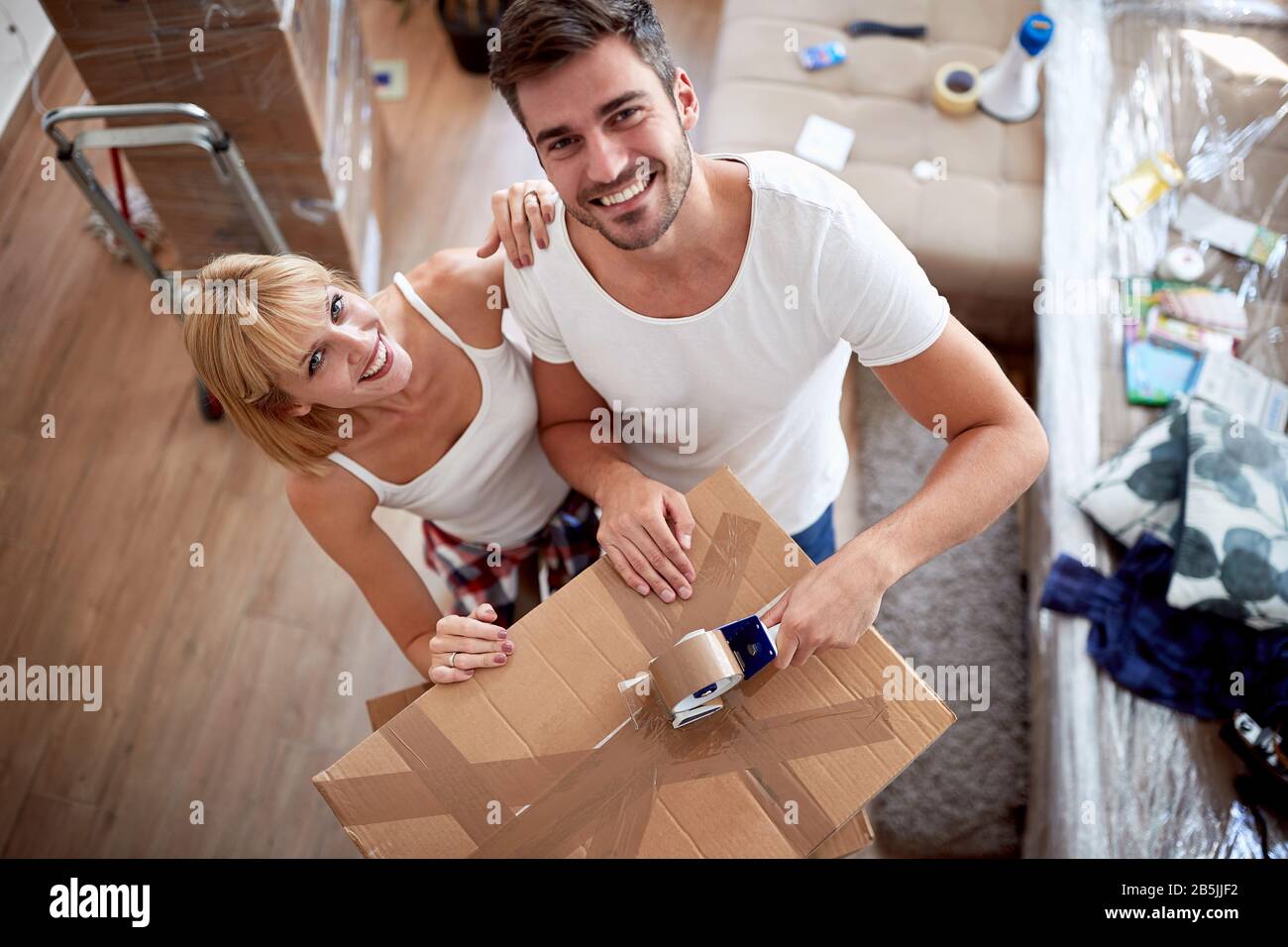 top view of couple in love while packing things in boxes for moving ...