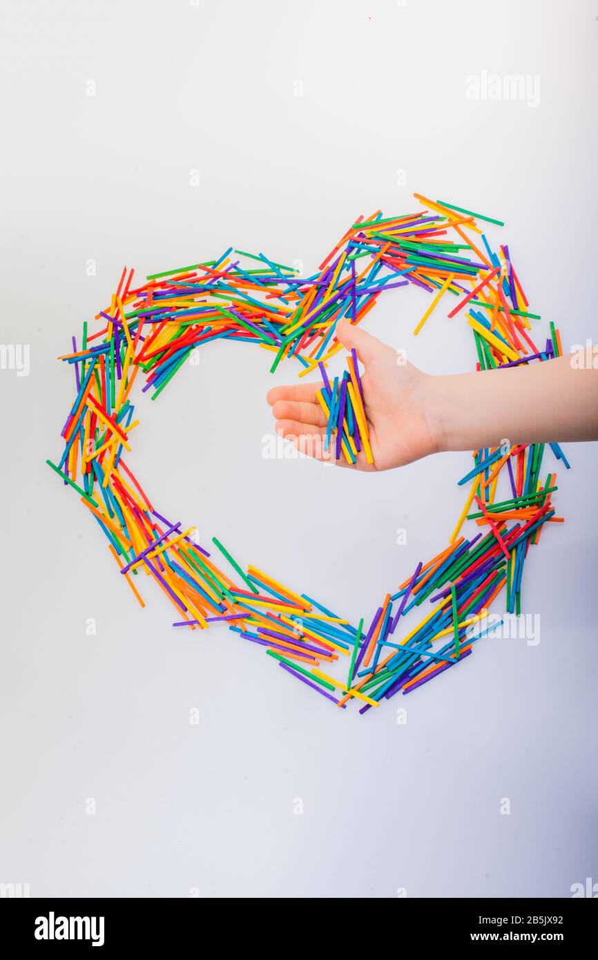Coloured sticks formed heart shape by hand on white background Stock ...