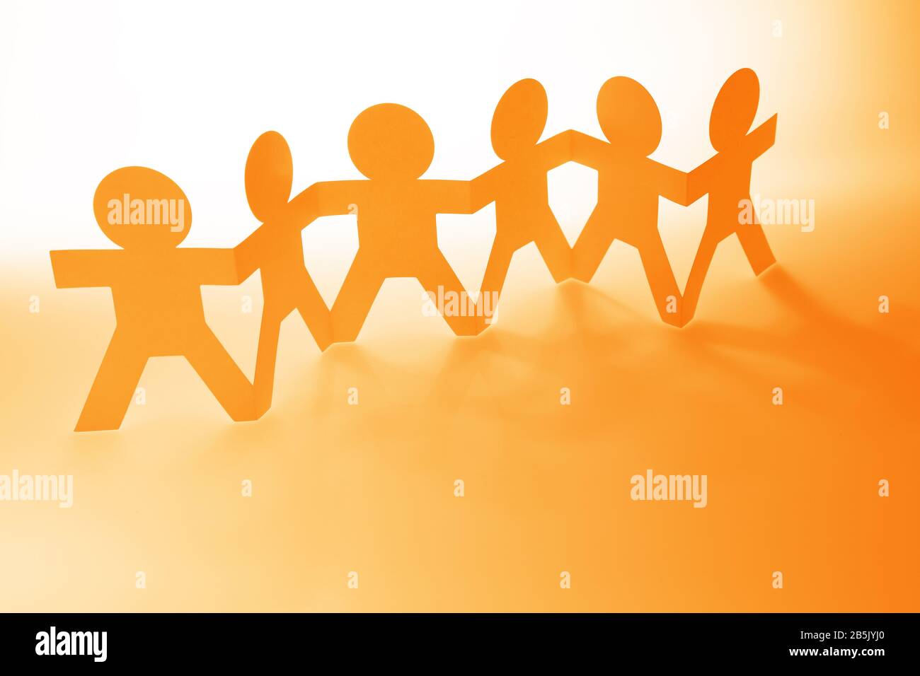 Paper chain team holding hands. Teamwork. Partnership Stock Photo - Alamy