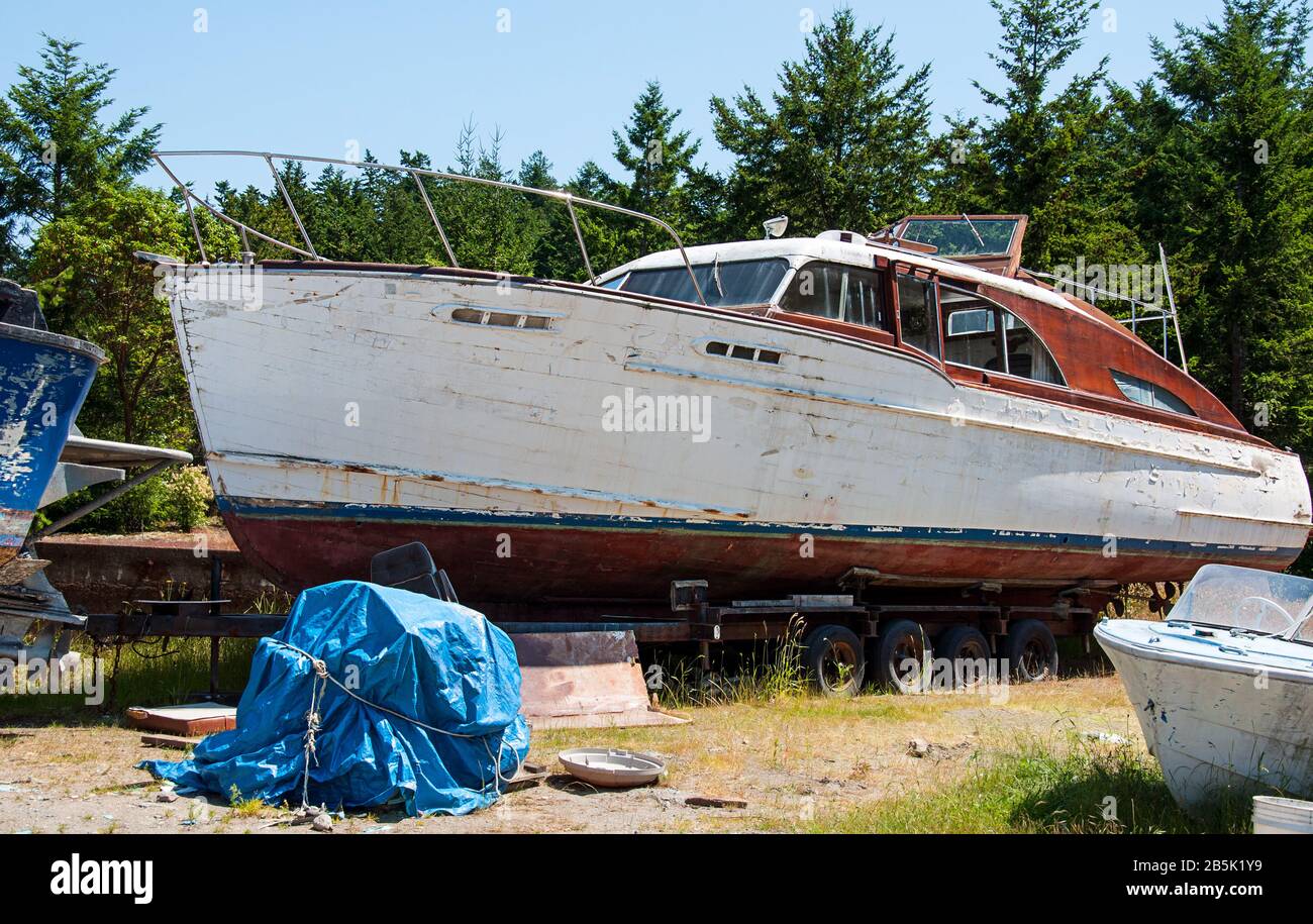 Boat dry docked for repairs in boat yard with smaller boat to the side ...