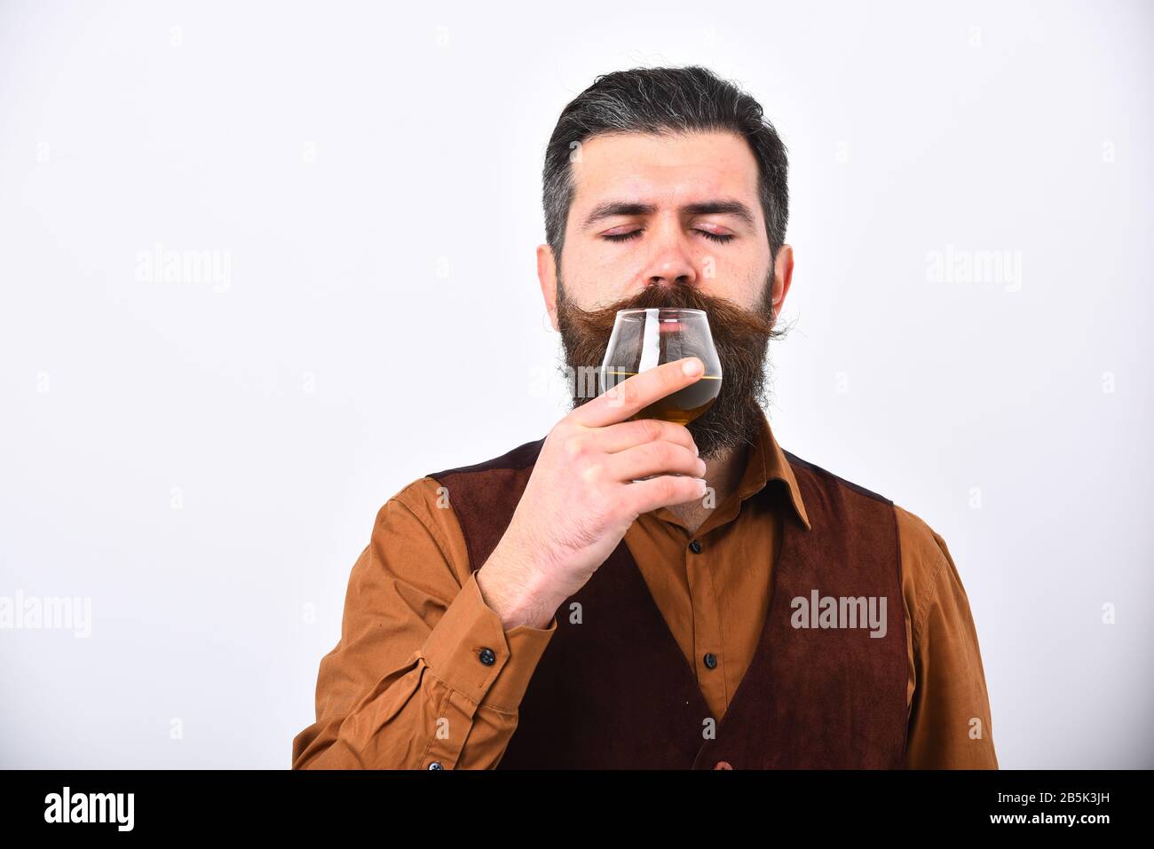 Barman or degustator with dreamy face tastes cognac. Waiter in elegant ...