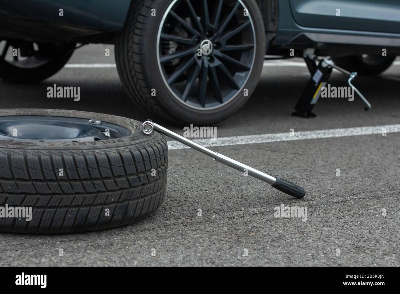 A flat tire car wheel and screwdriver are on a asphalt road on the ...